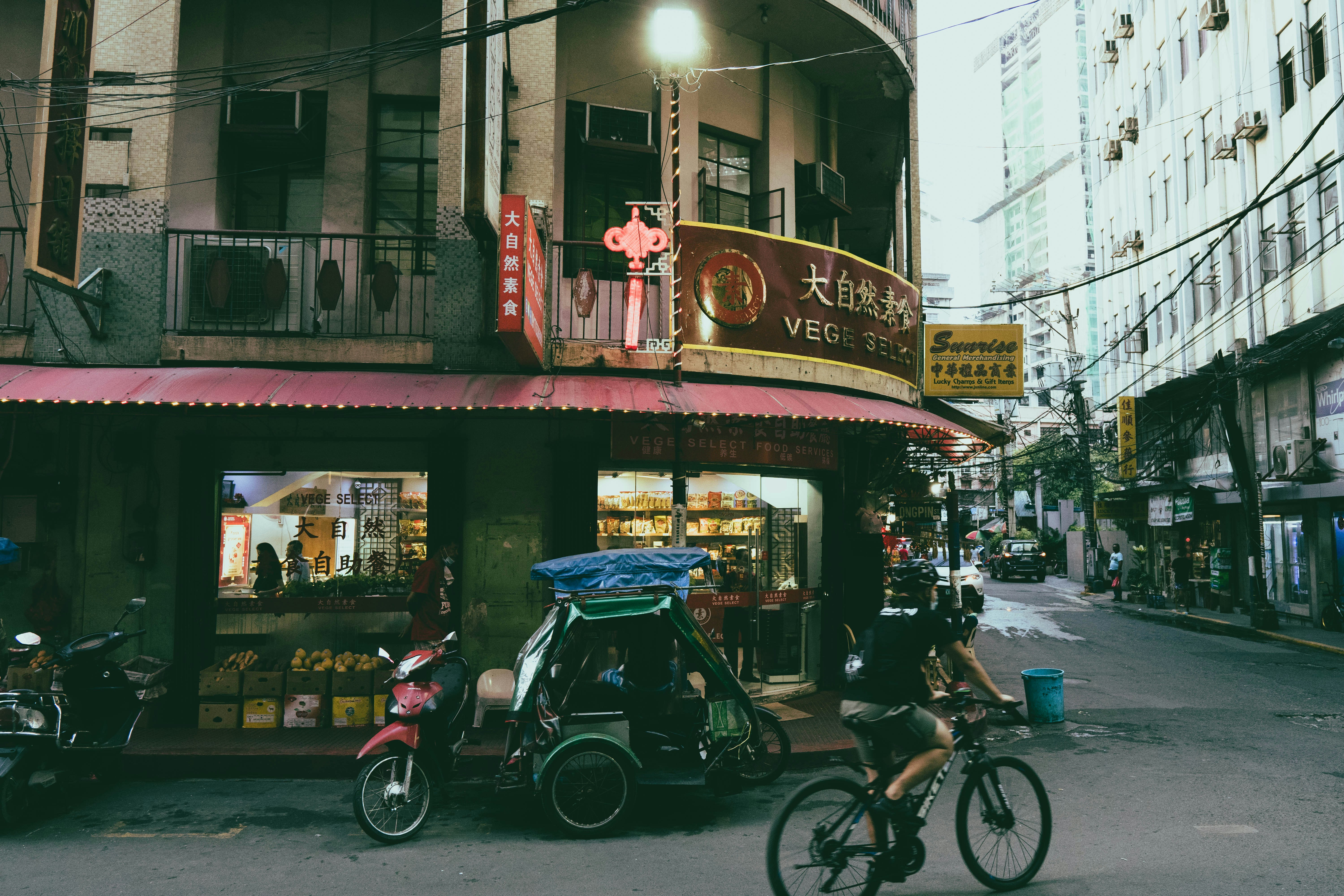 Bicyclist and motorcycle near a vintage storefront on a bustling city street.