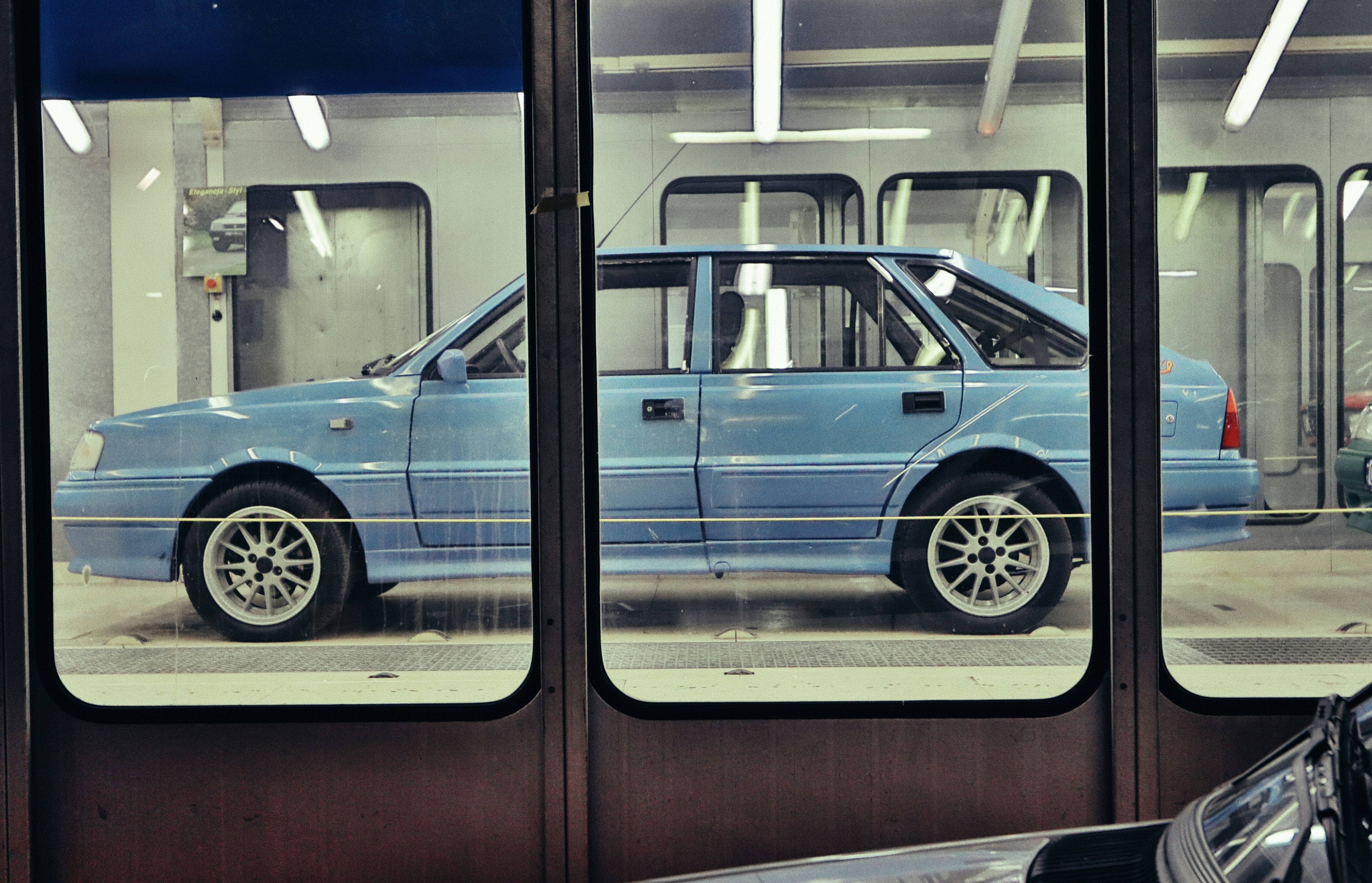 Blue Classic Sedan Framed by Glass Showroom Windows