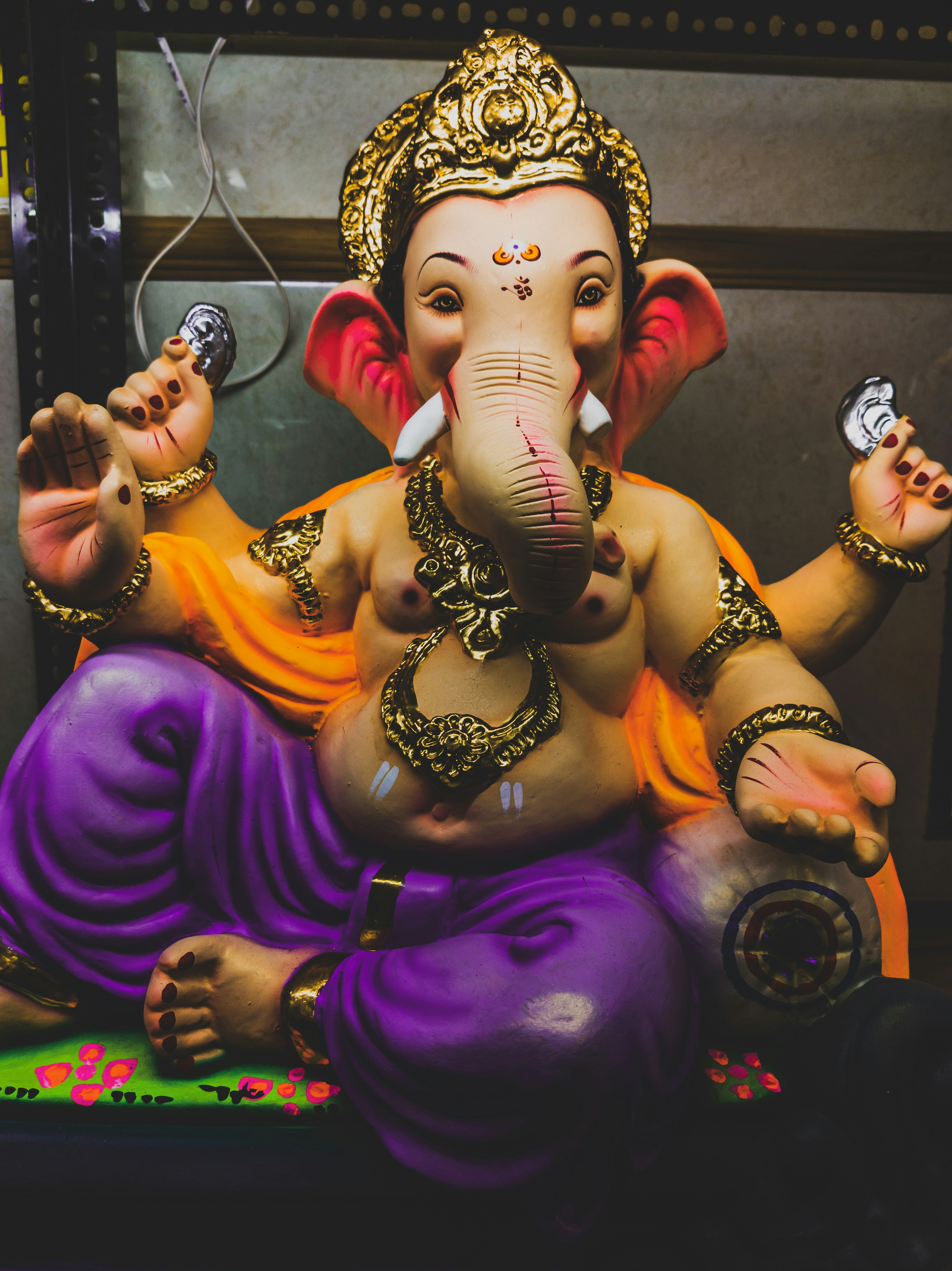 Vibrant statue of Lord Ganesha adorned in colorful attire, showcasing intricate details and a serene expression.