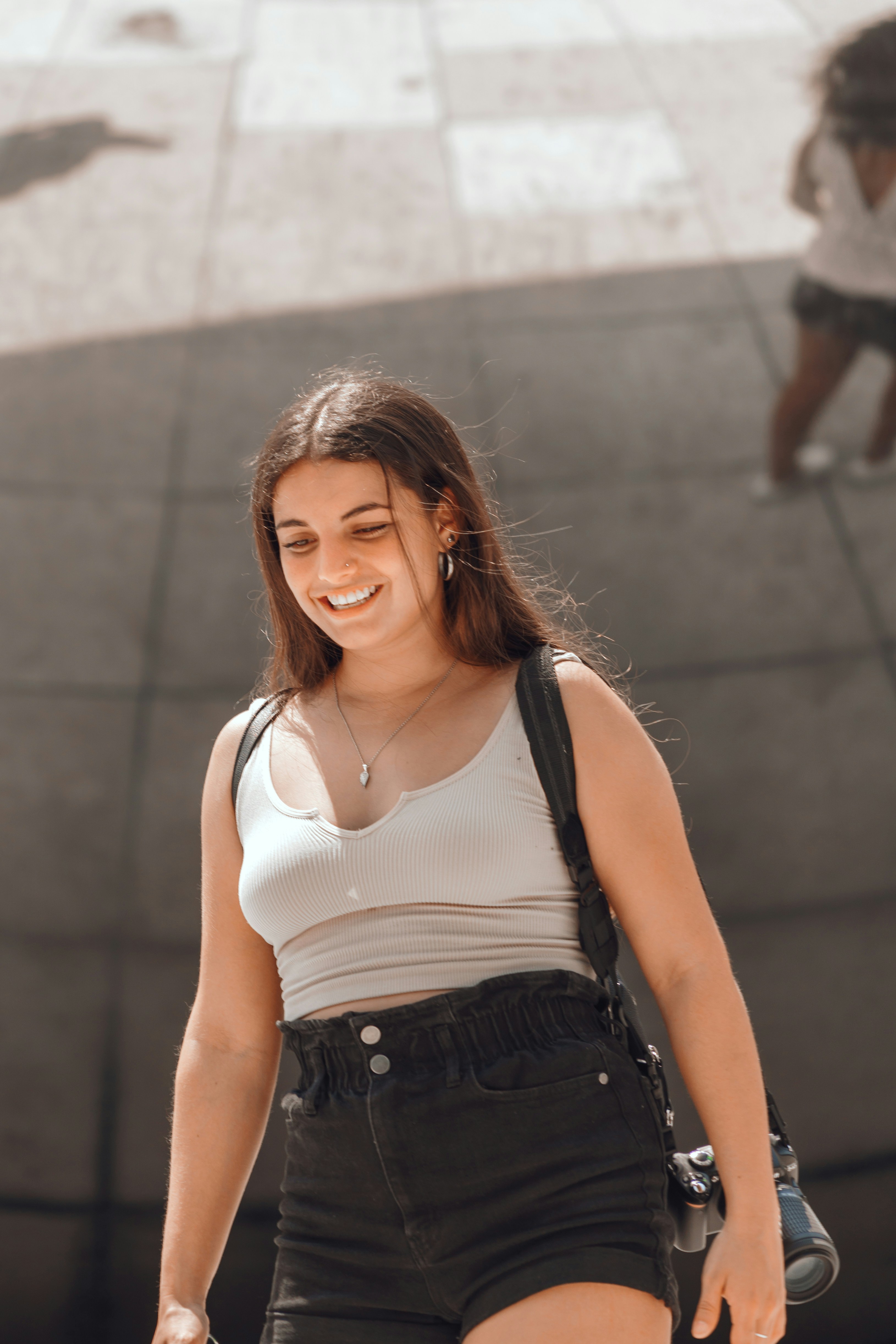 Sunlit City Smile: A candid portrait with a camera at her side