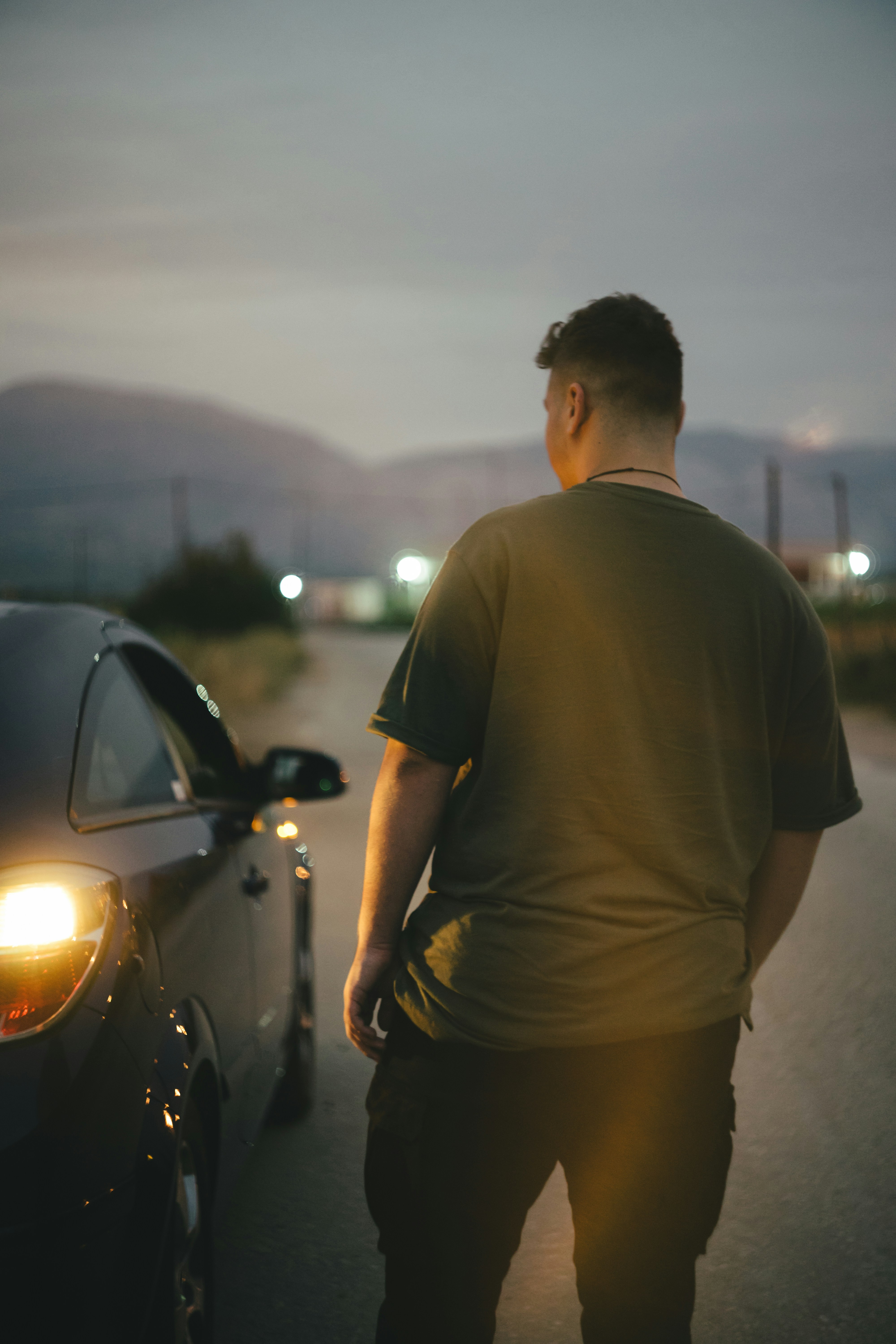 Twilight Pause on a Desert Road: A Man Beside the Glowing Car
