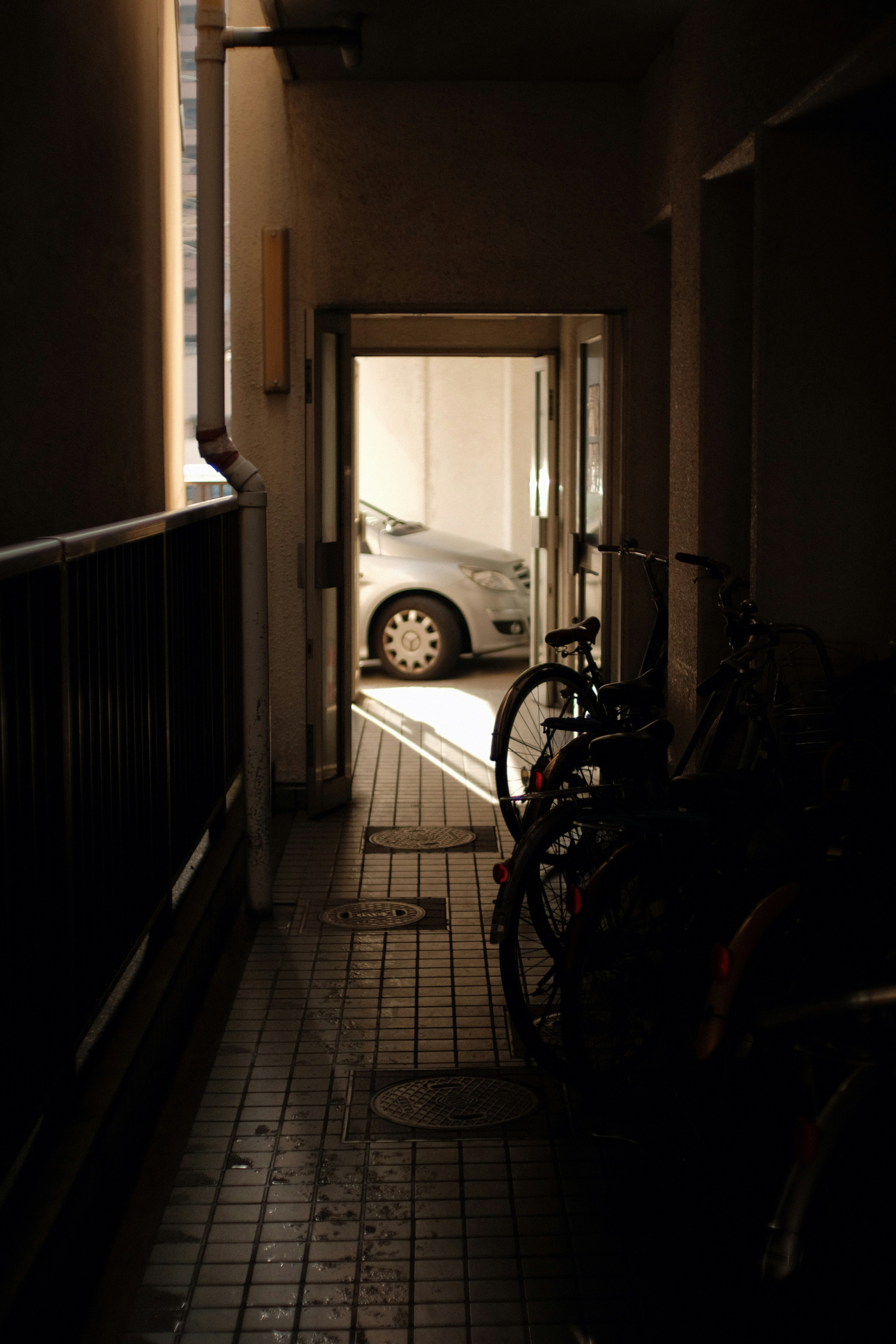 Exit Framing: a Silver Car Anchored by a Shadowed Corridor