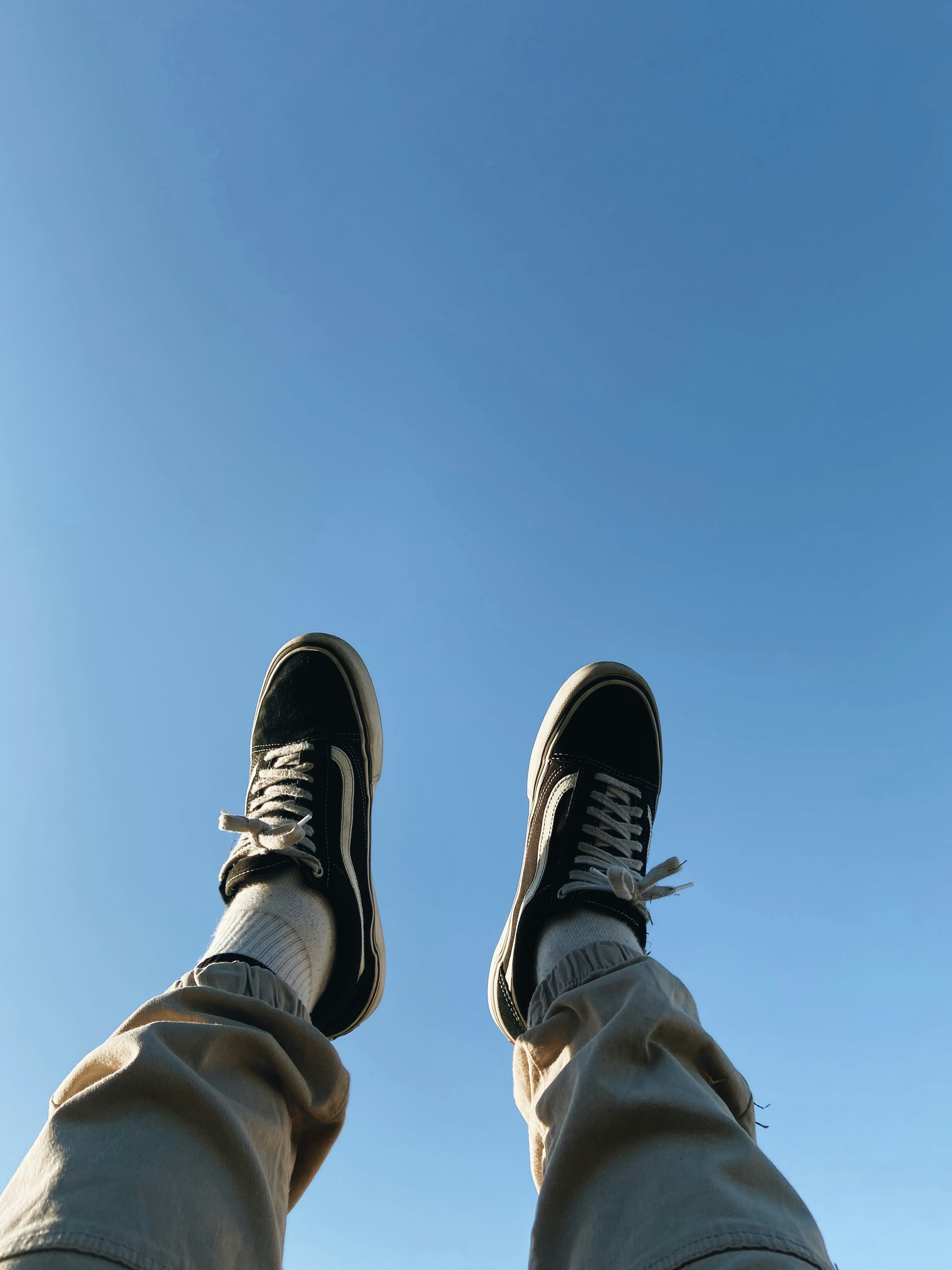 Feet dangling against a clear blue sky, capturing a moment of leisure and reflection.