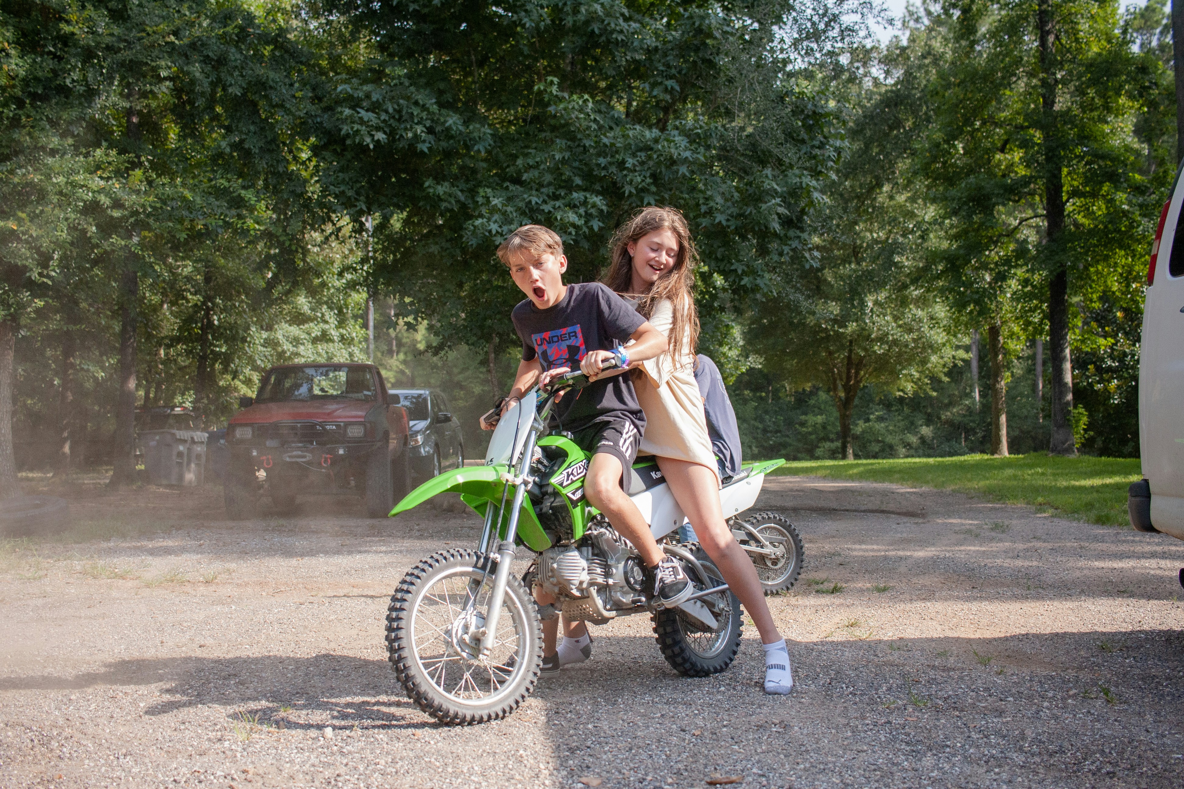 Dusty Duo on a Lime Dirt Bike: Sunlit Playground Moment