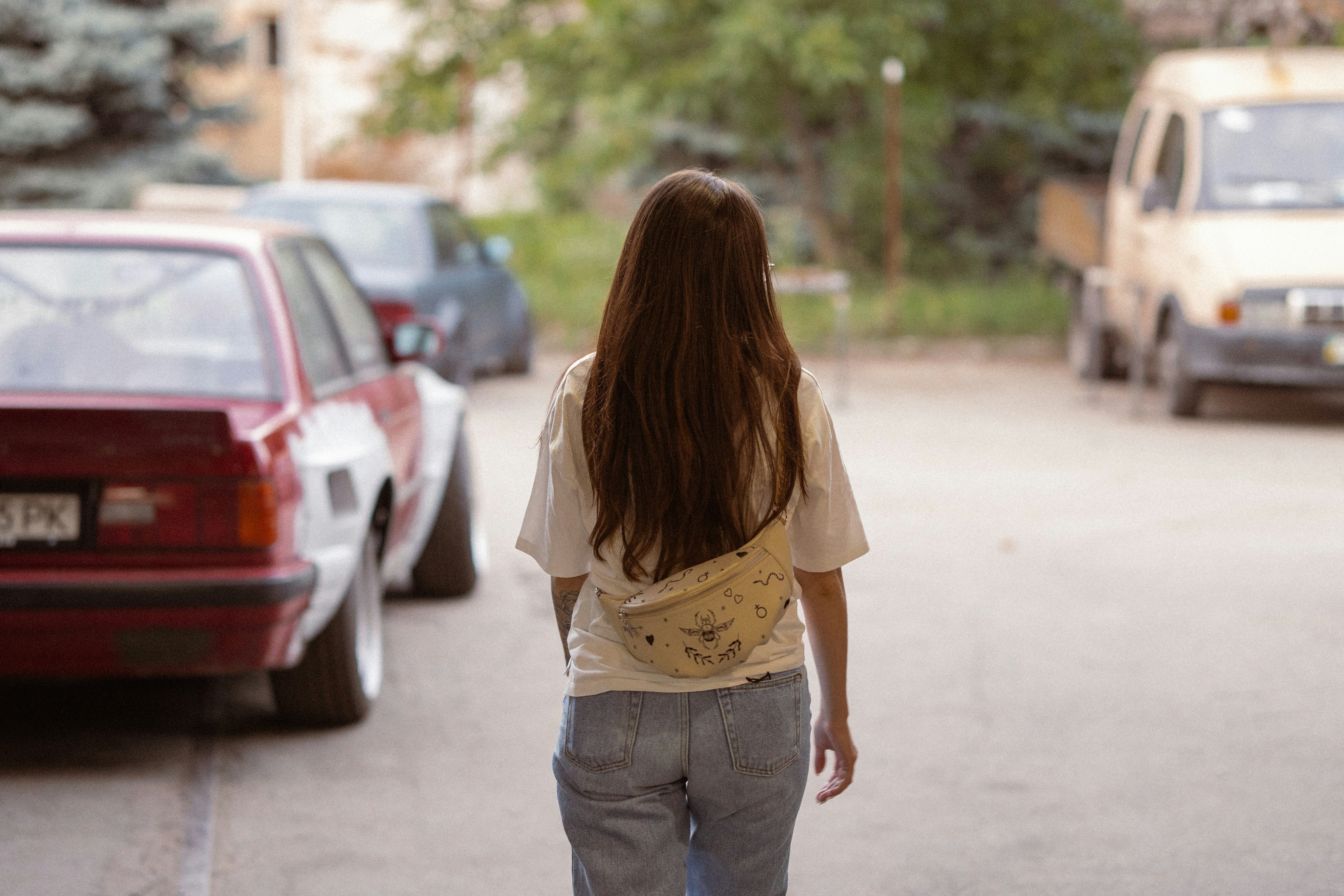woman in white shirt and blue denim jeans standing on road during daytime