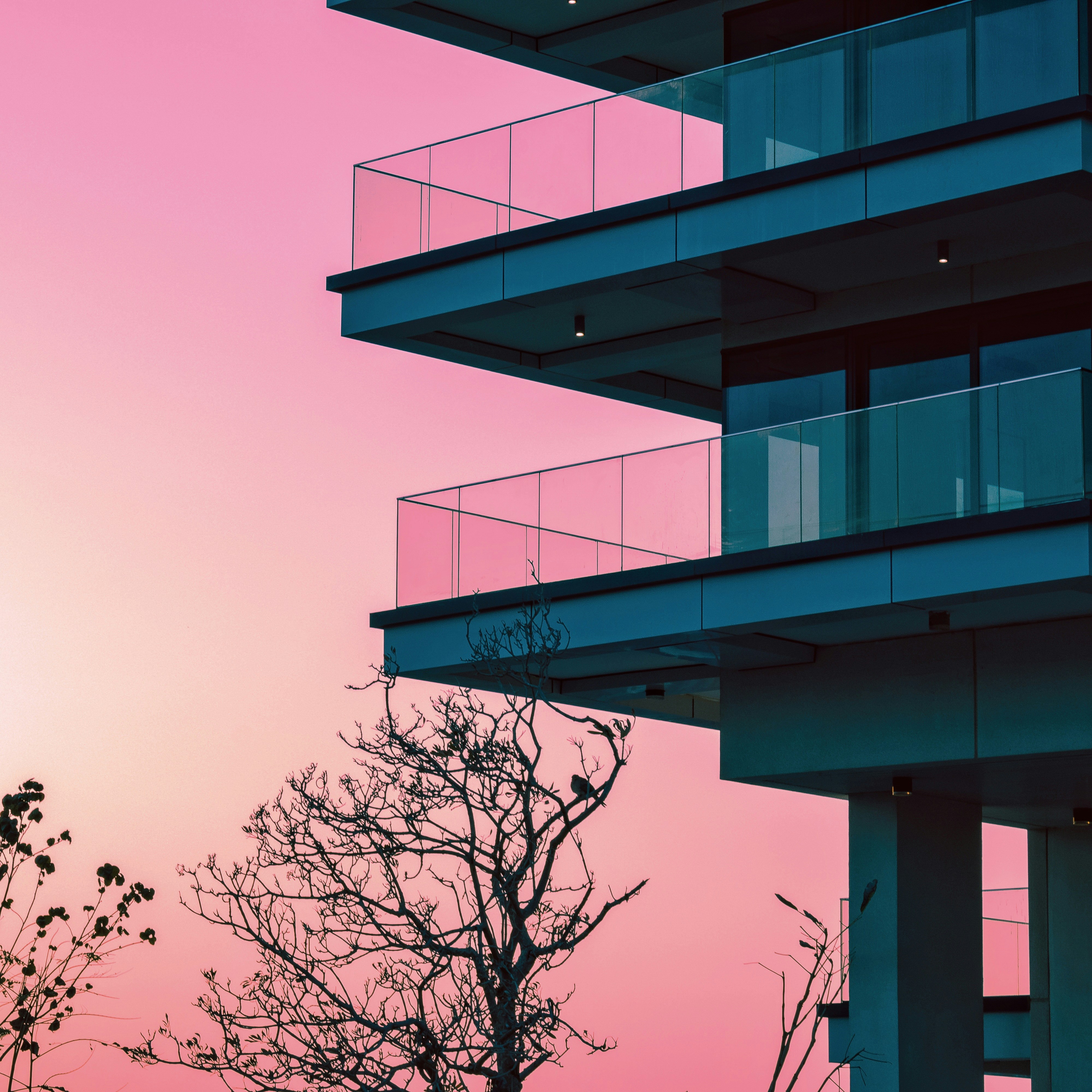 Modern architectural structure silhouetted against a vibrant pink and purple sky at sunset.