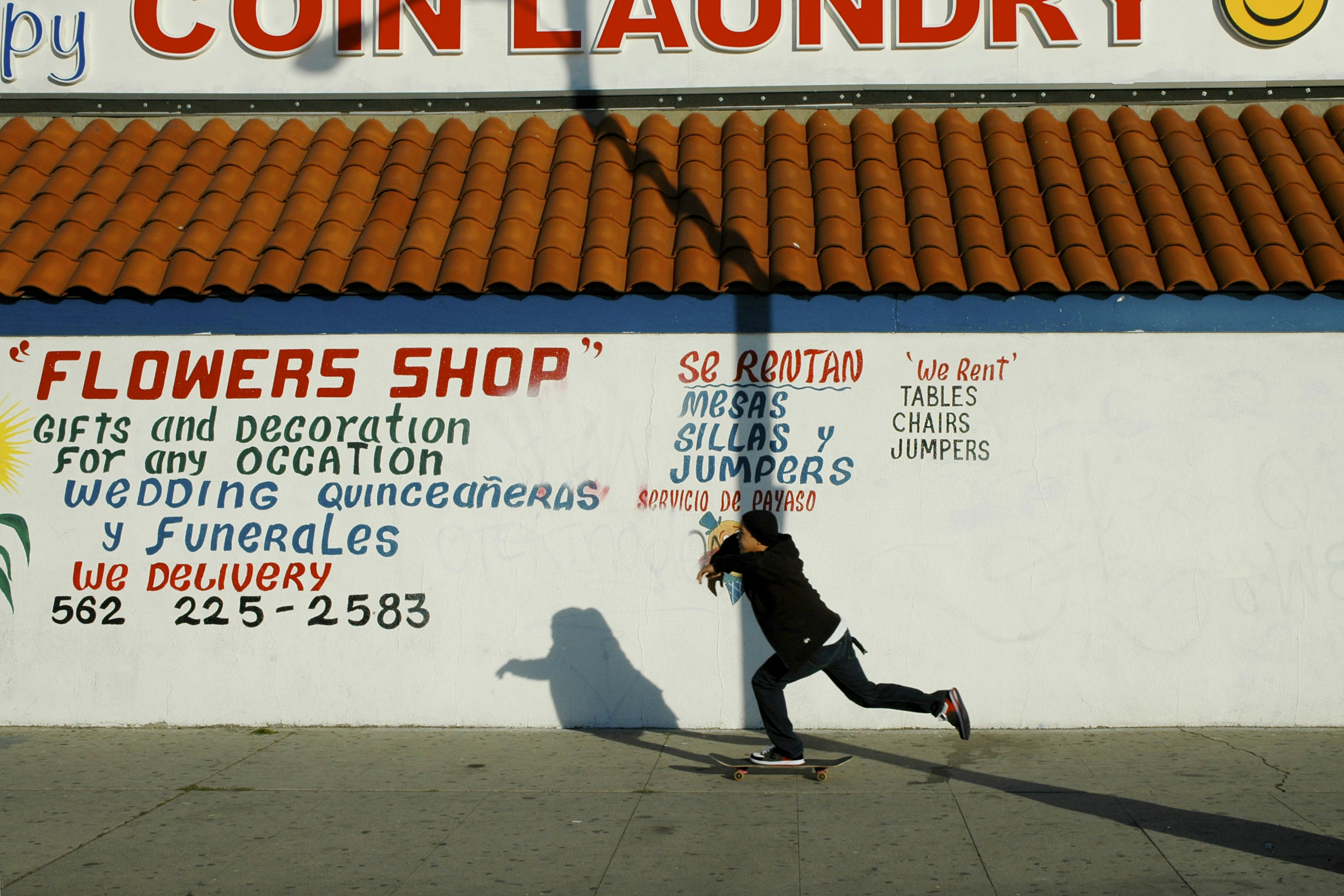 Person in motion against a white wall with colorful signage and vivid shadows.