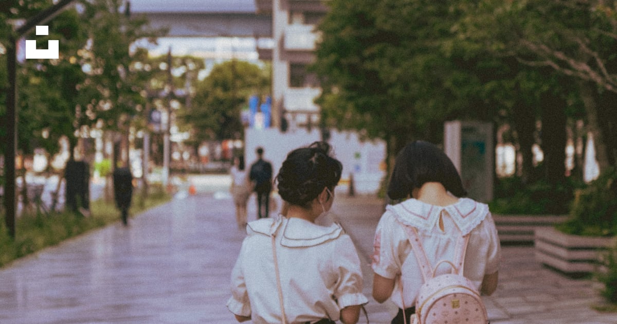 낮 동안 보도를 걷고 있는 흰 코트를 입은 여성 2명 사진 Unsplash의 무료 건물 이미지