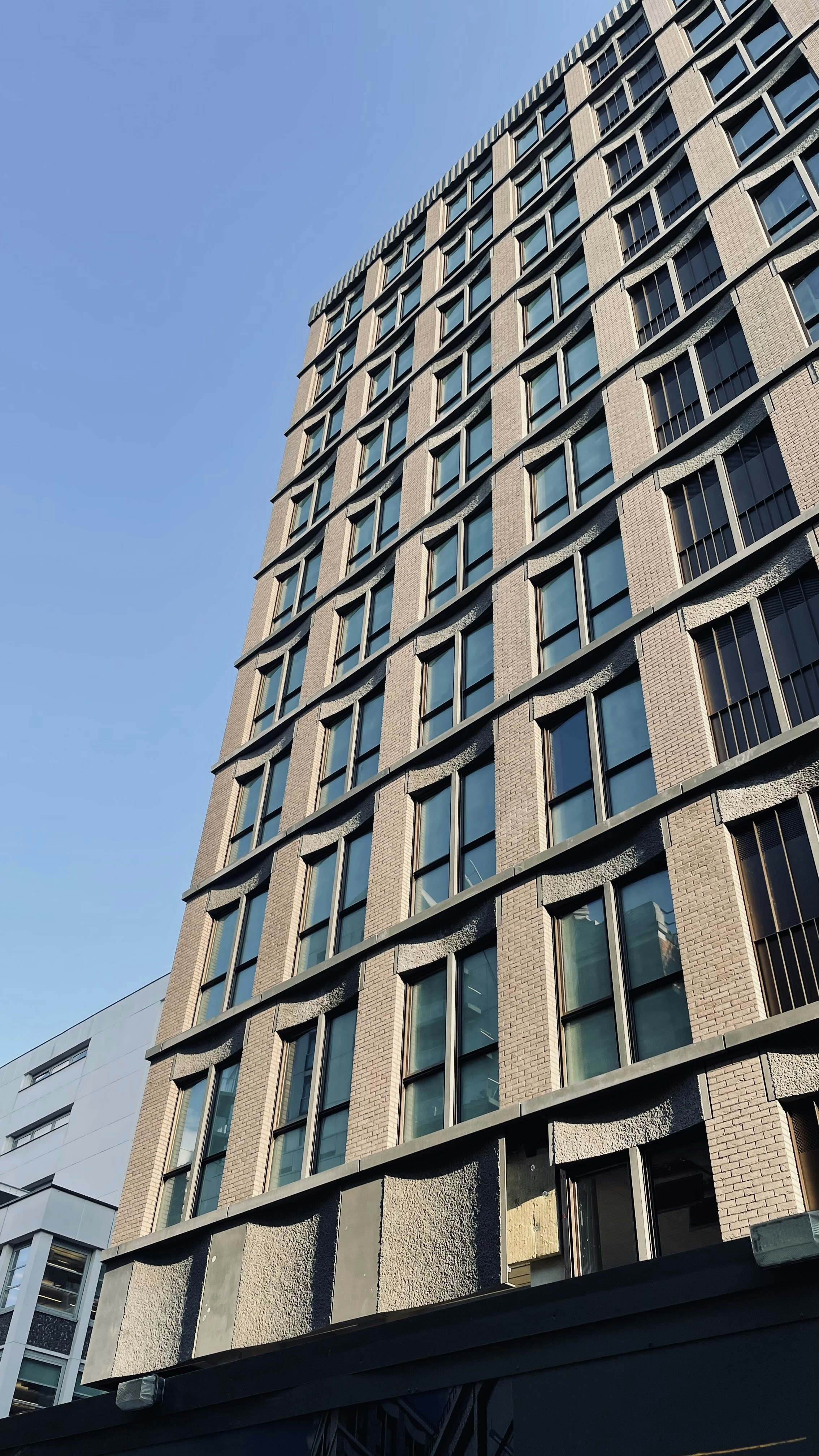 A tall building showcasing a modern architectural design with a mix of brick and glass elements against a clear blue sky.