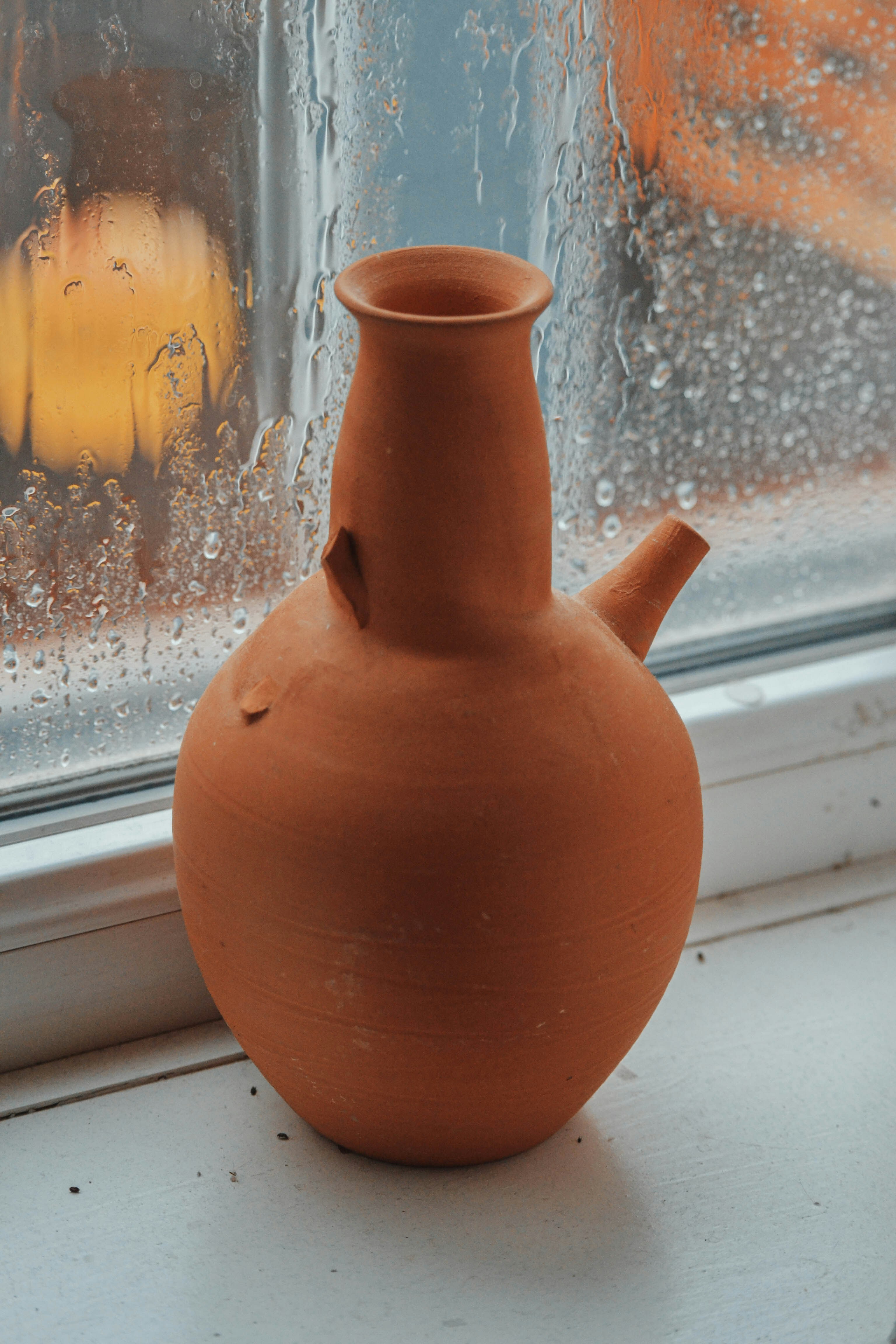 Terracotta Vessel Bathed in Rain-Streaked Window Light