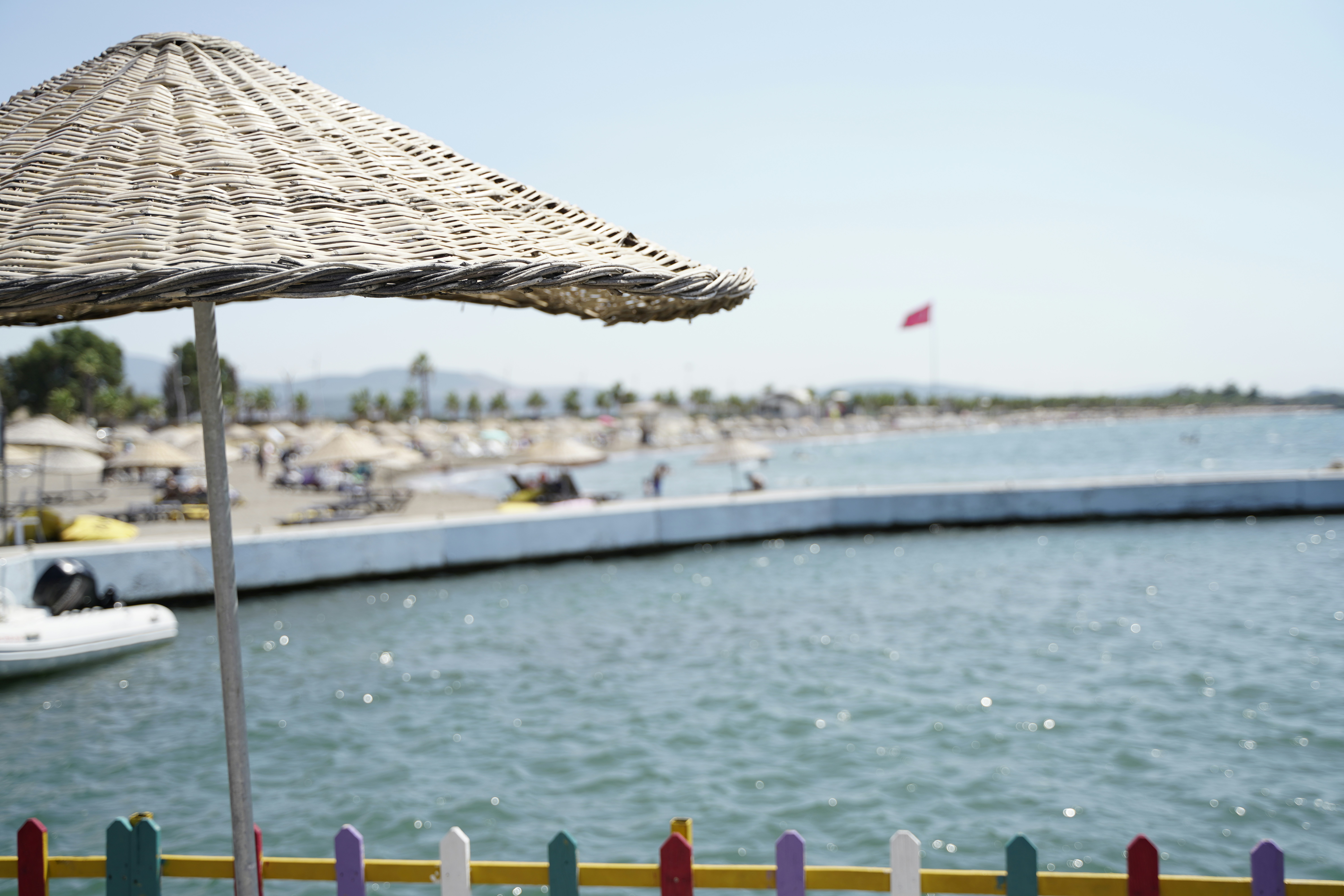 Sunlit Cove: Beach Umbrella Frame Over a Colorful Seaside Fence