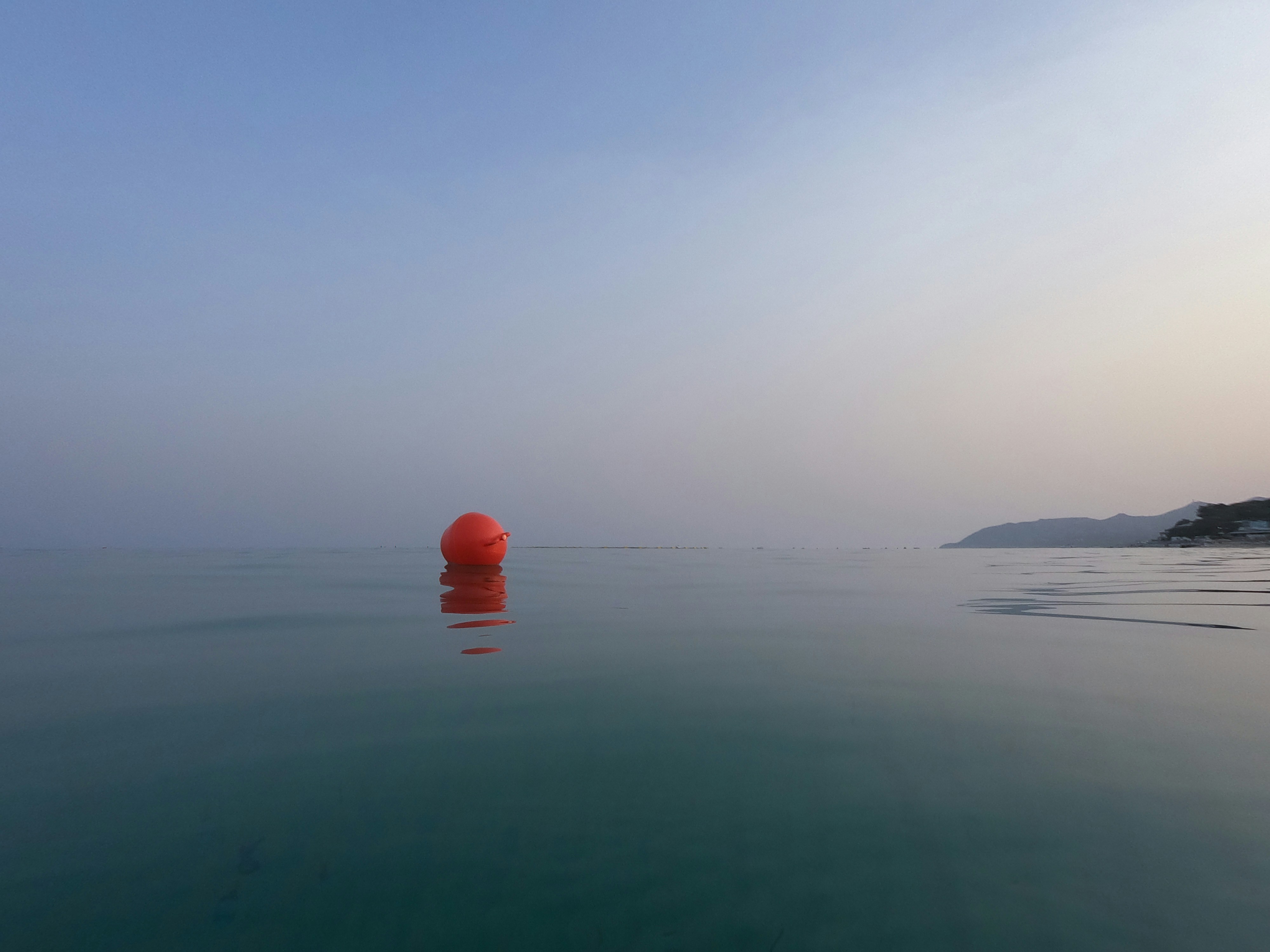 red plastic bottle on body of water during daytime