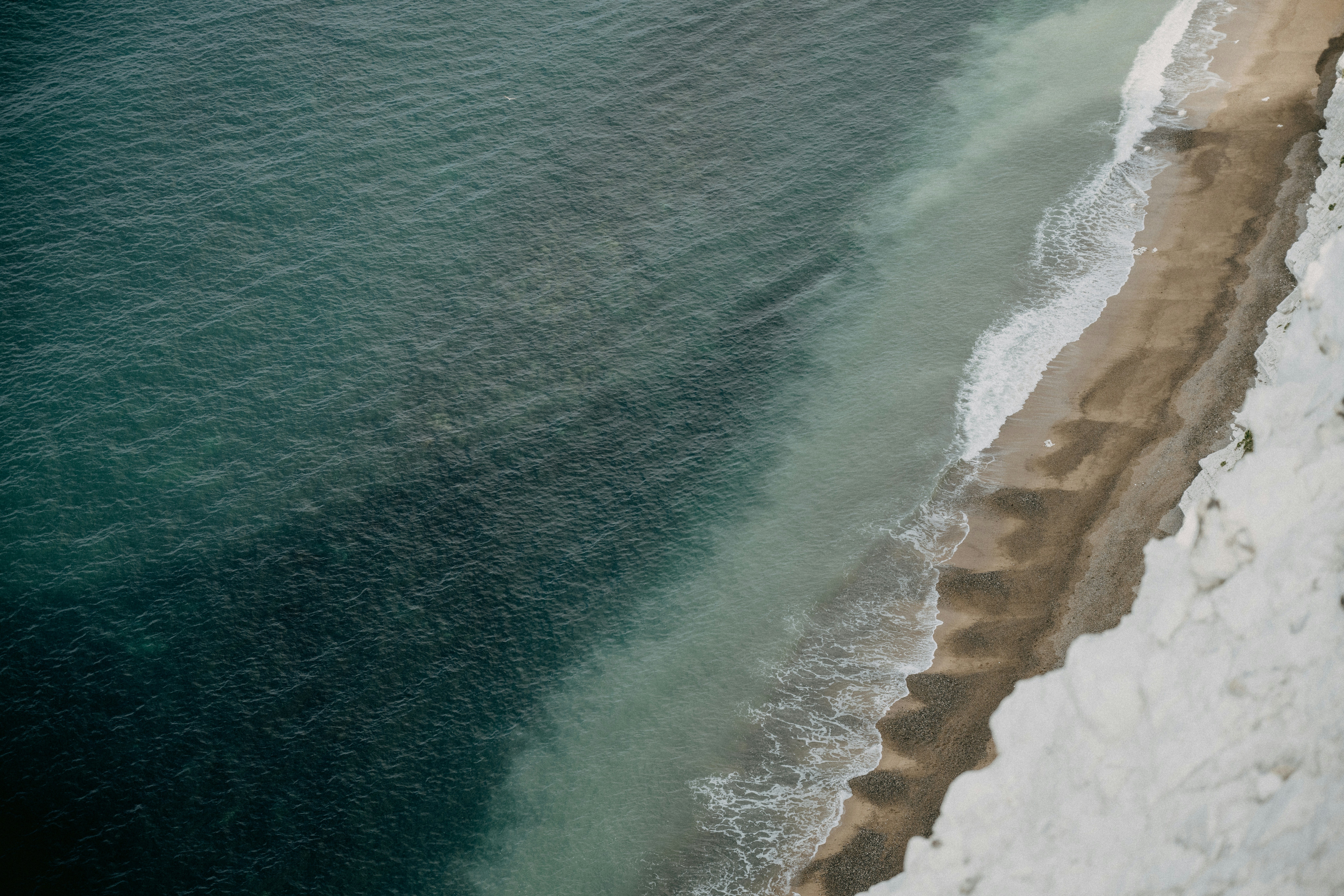 Aerial view of a serene coastline with gentle waves meeting the sandy shore.