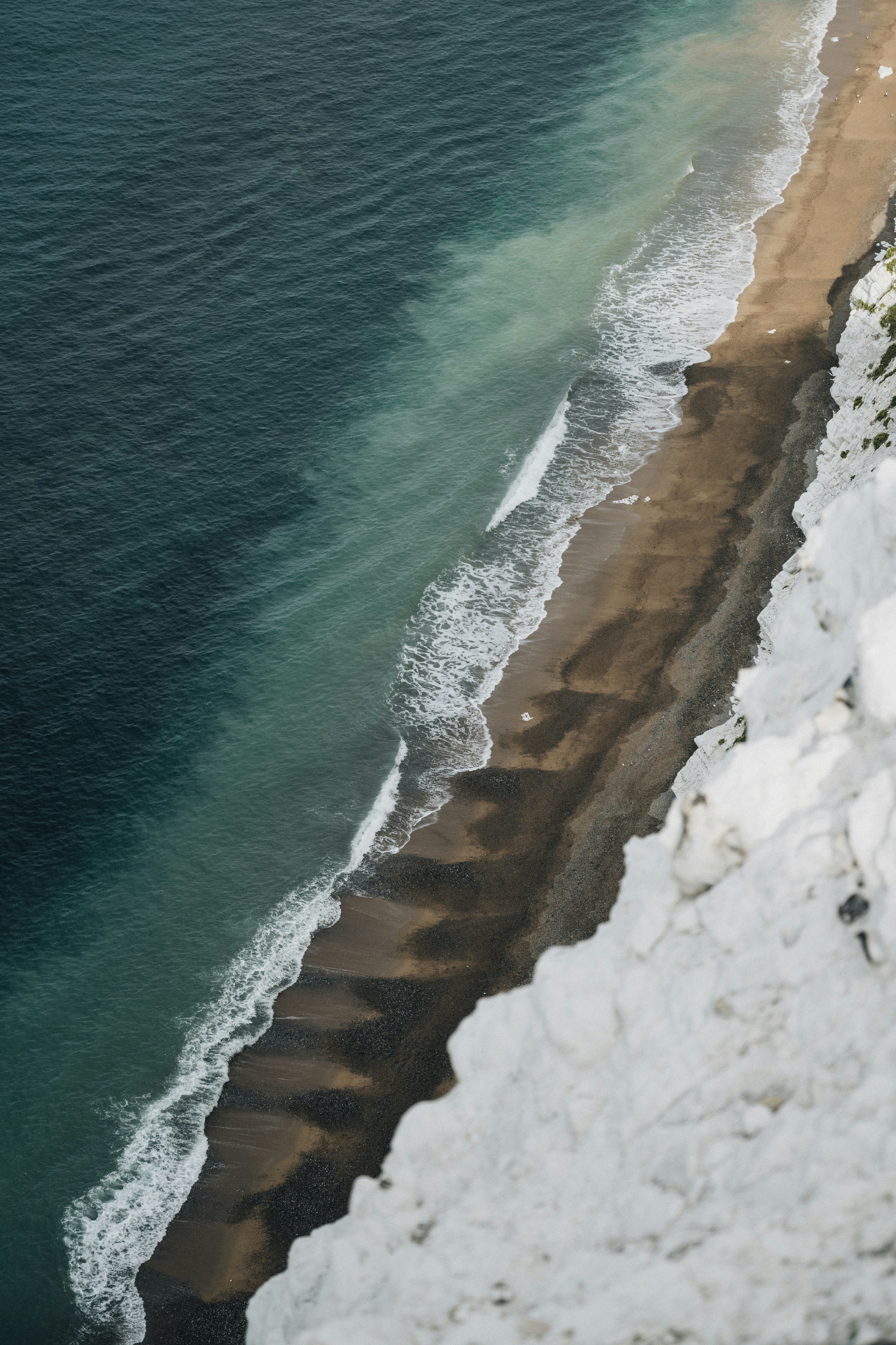 Cliffside Ballet: chalk-white cliffs meet turquoise shoreline from above