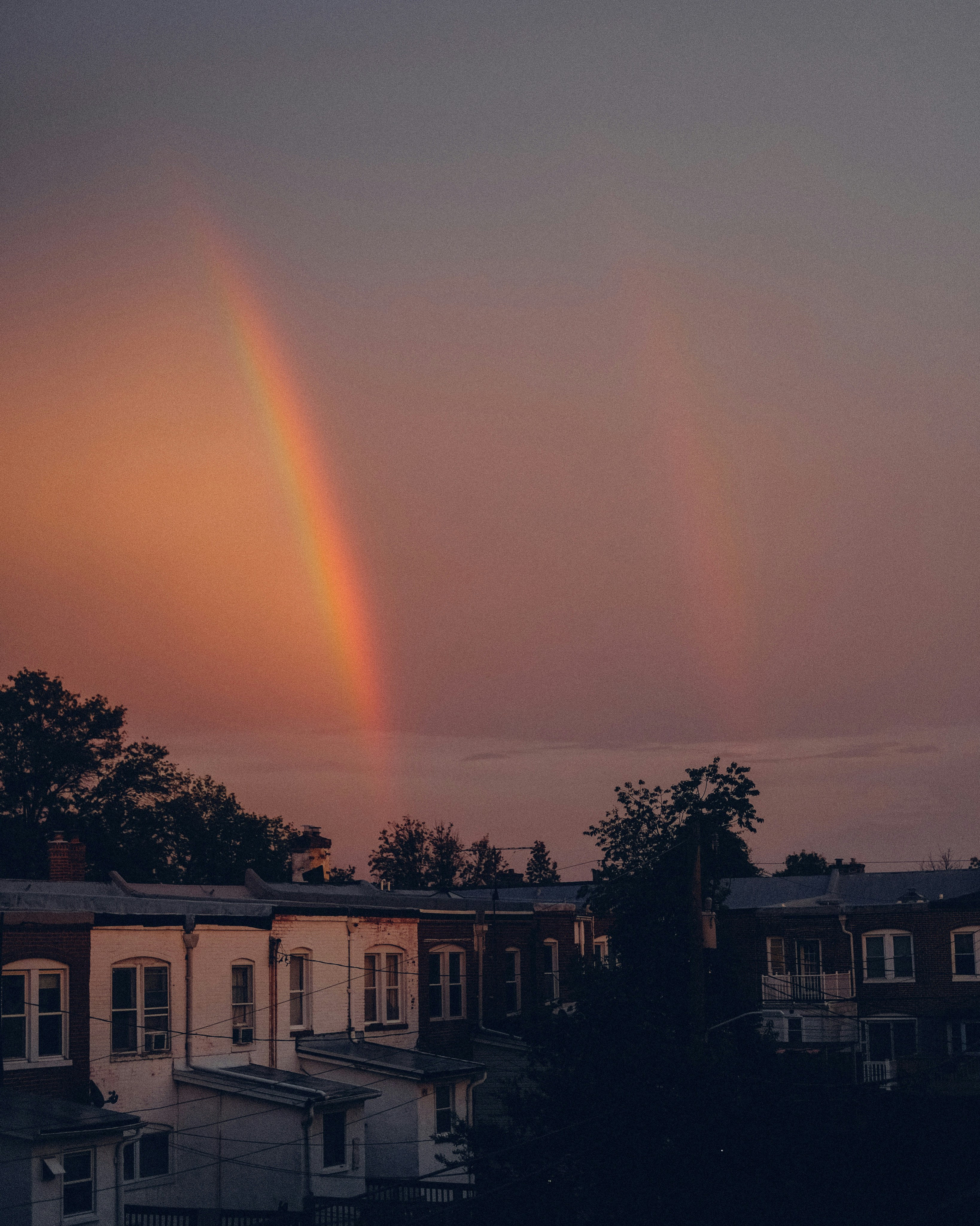 Twin Rainbows Crown a Quiet Sunset Over Urban Rooftops