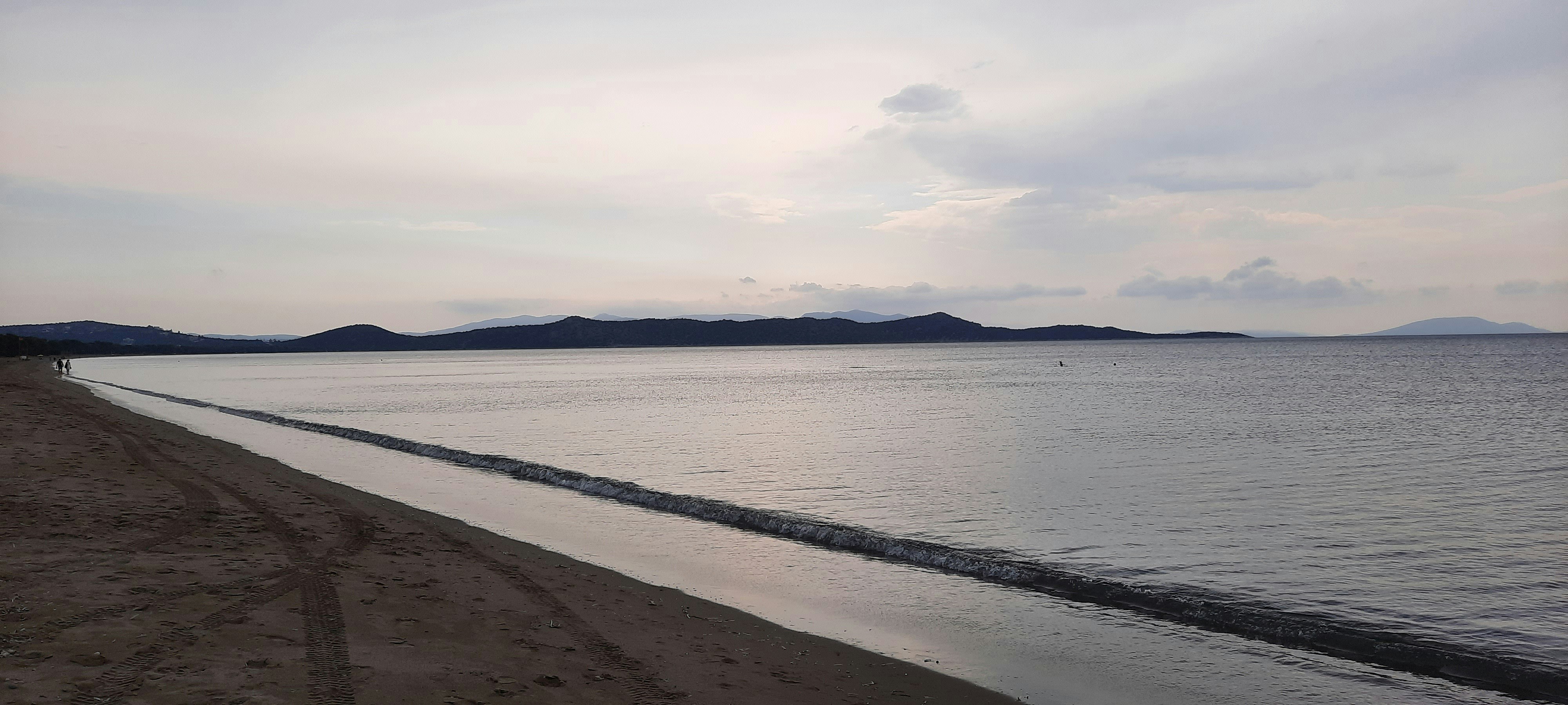 Overcast sky reflected on a calm sea with a distant shoreline.