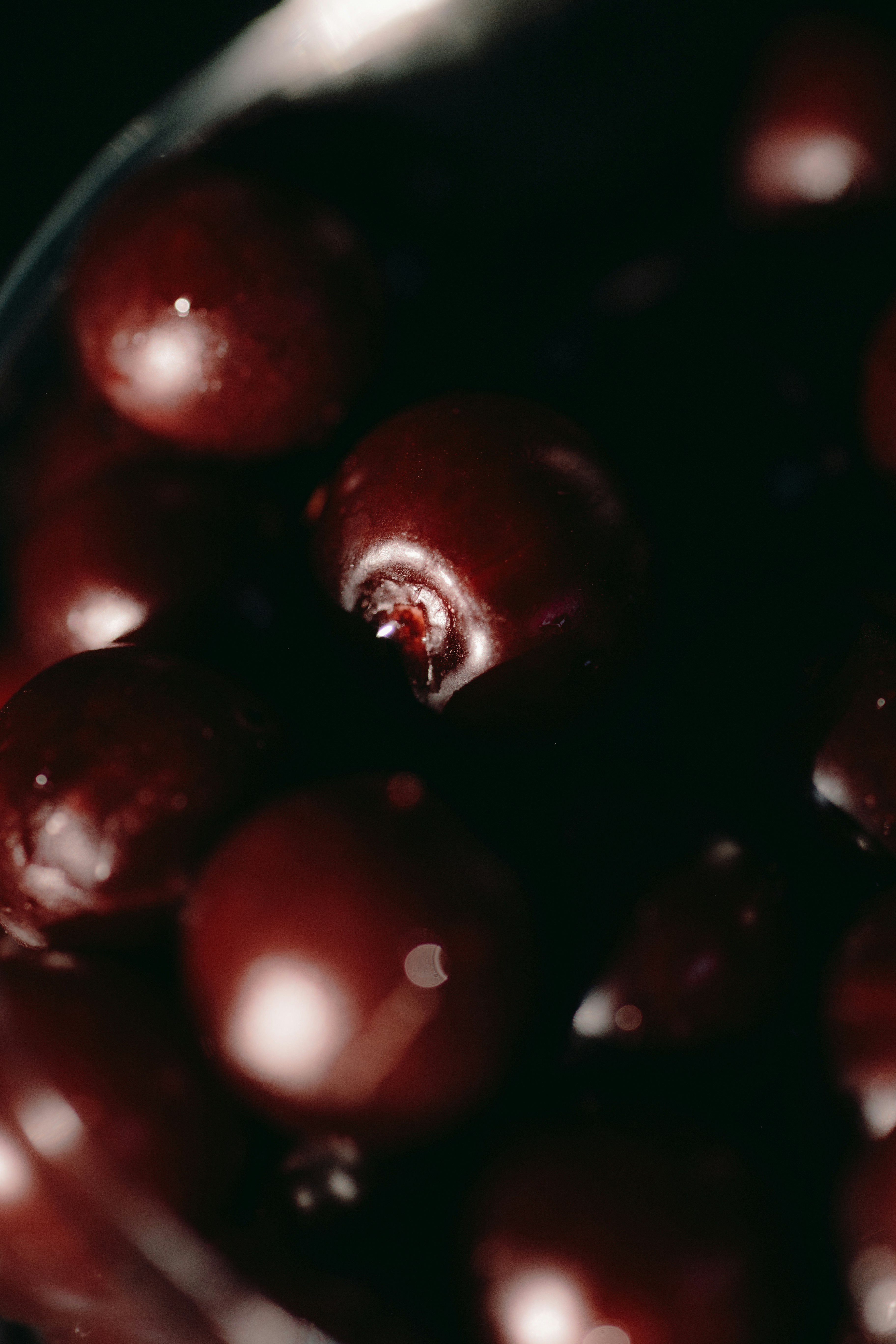 Close-up of glossy dark cherries resting in a bowl, highlighting their vibrant color and texture.