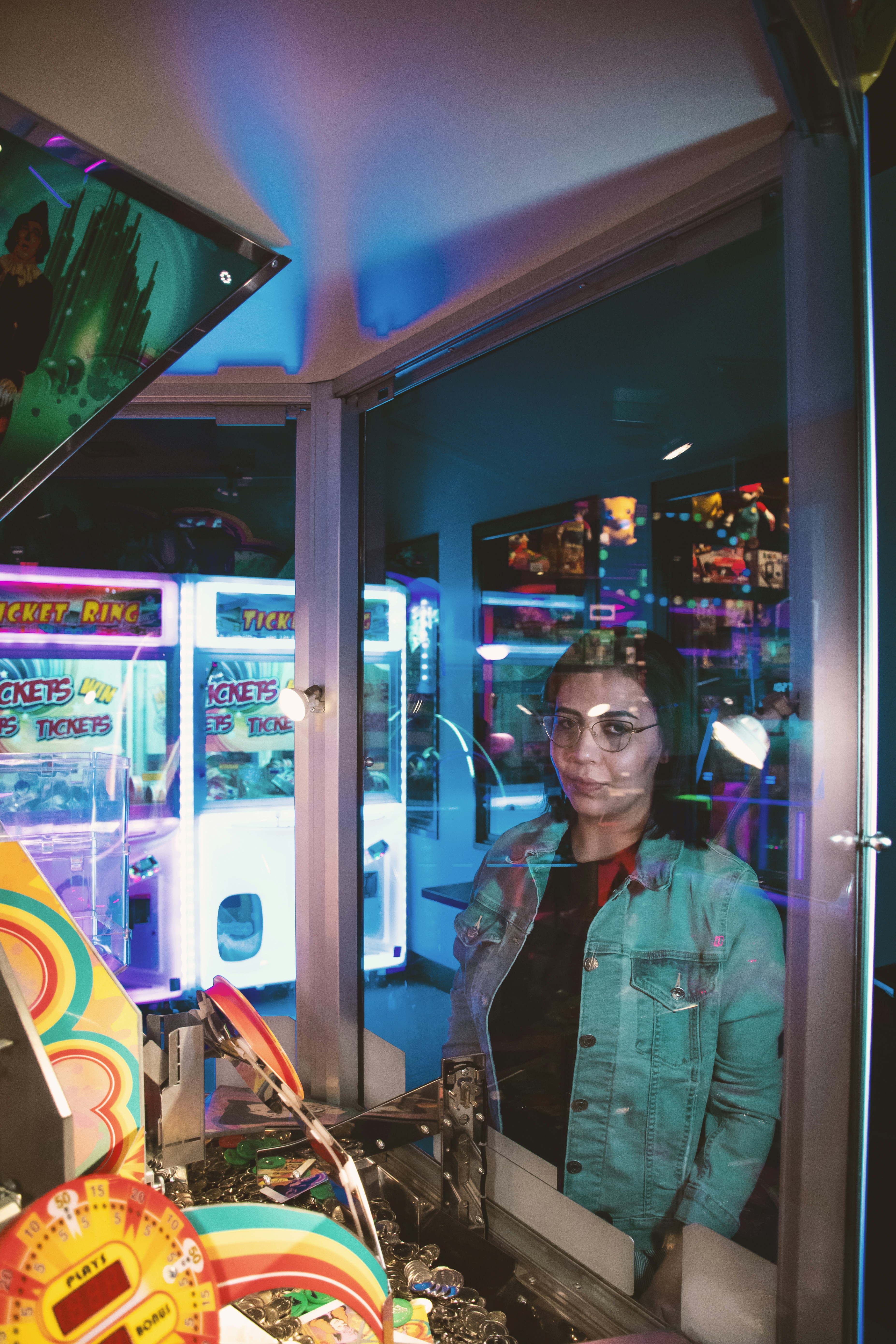 Denim Under Neon: A Quiet Portrait Reflected in Arcade Glass
