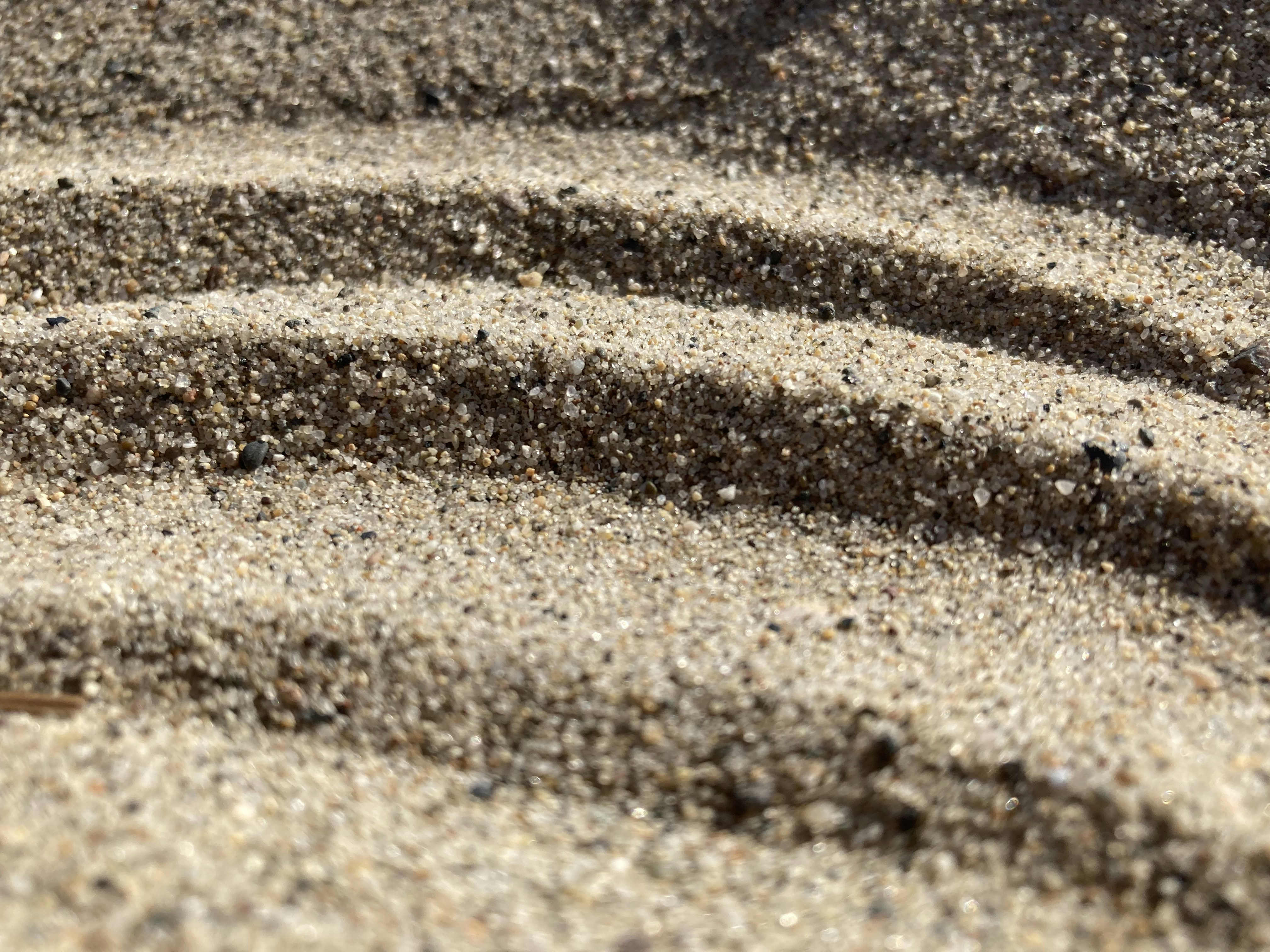 Close-up of gently undulating sand patterns, showcasing the intricate texture and natural formations created by wind and movement.