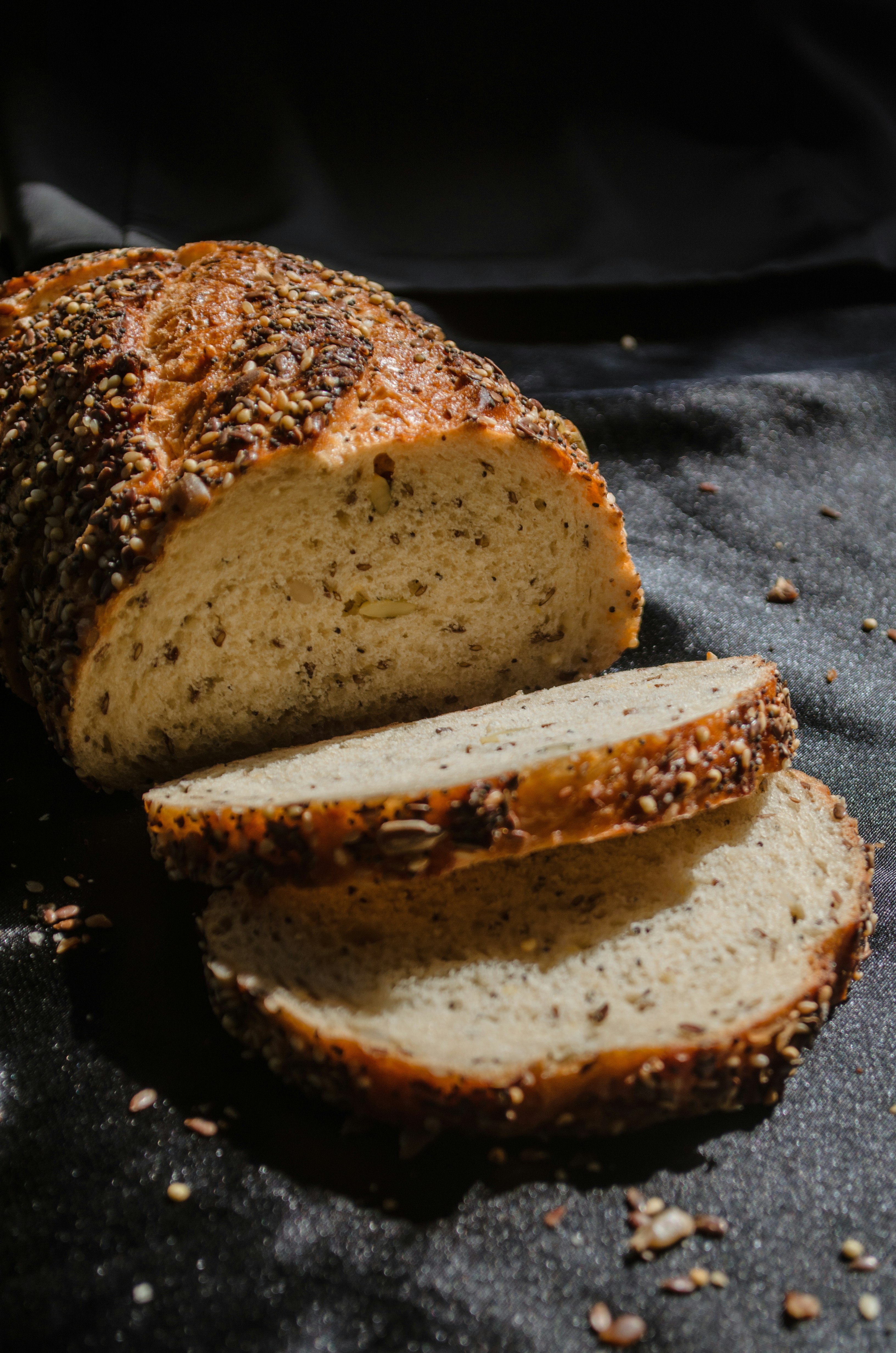 Freshly baked artisan bread loaf with a crusty exterior and visible seeds, sliced to reveal its soft interior. Perfect for showcasing culinary craftsmanship.