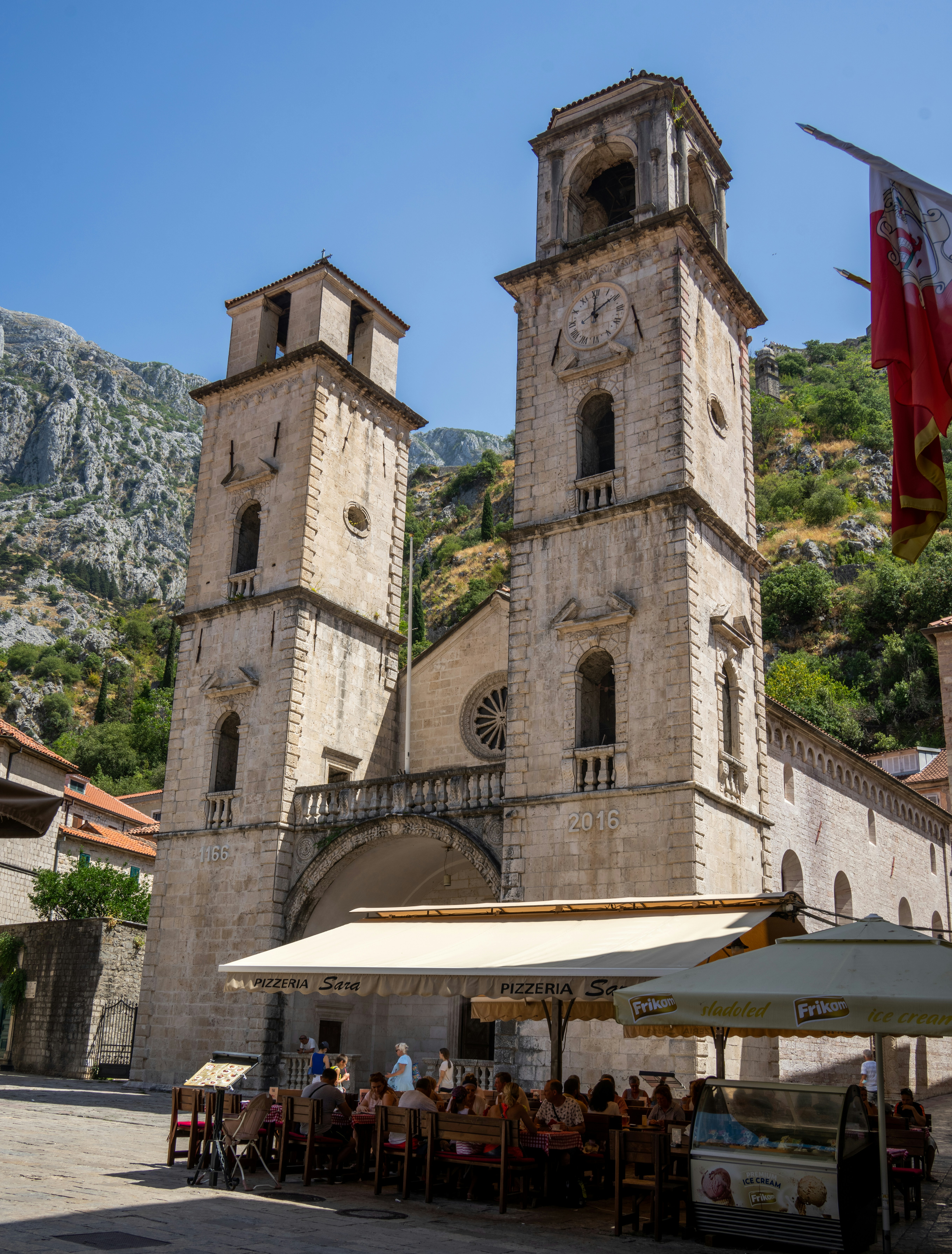 Twin Bell Towers Over a Sunlit Stone Courtyard Café