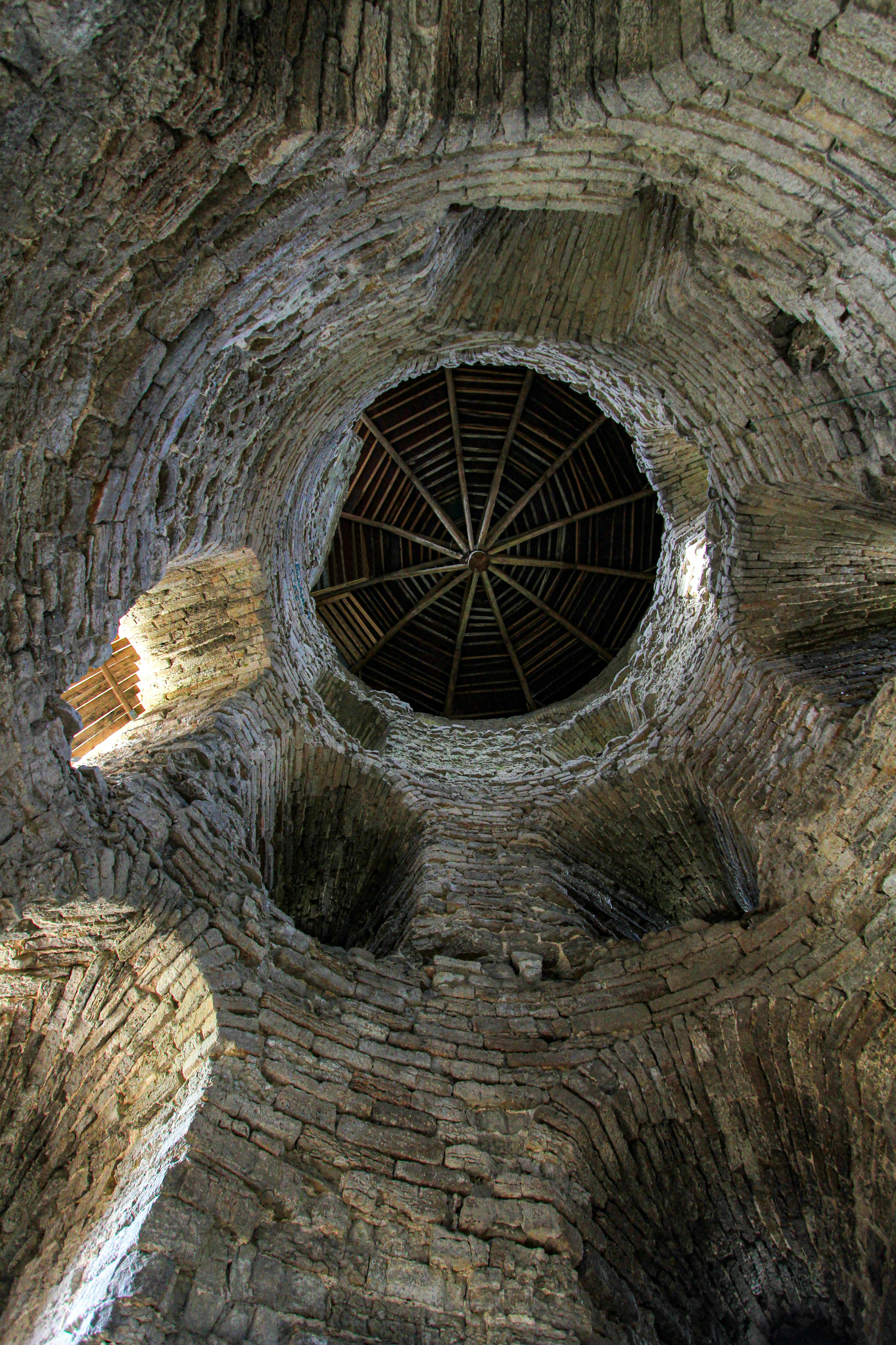 Spiral Stone Vault: A Skyward View Through a Wooden-Spoked Roof