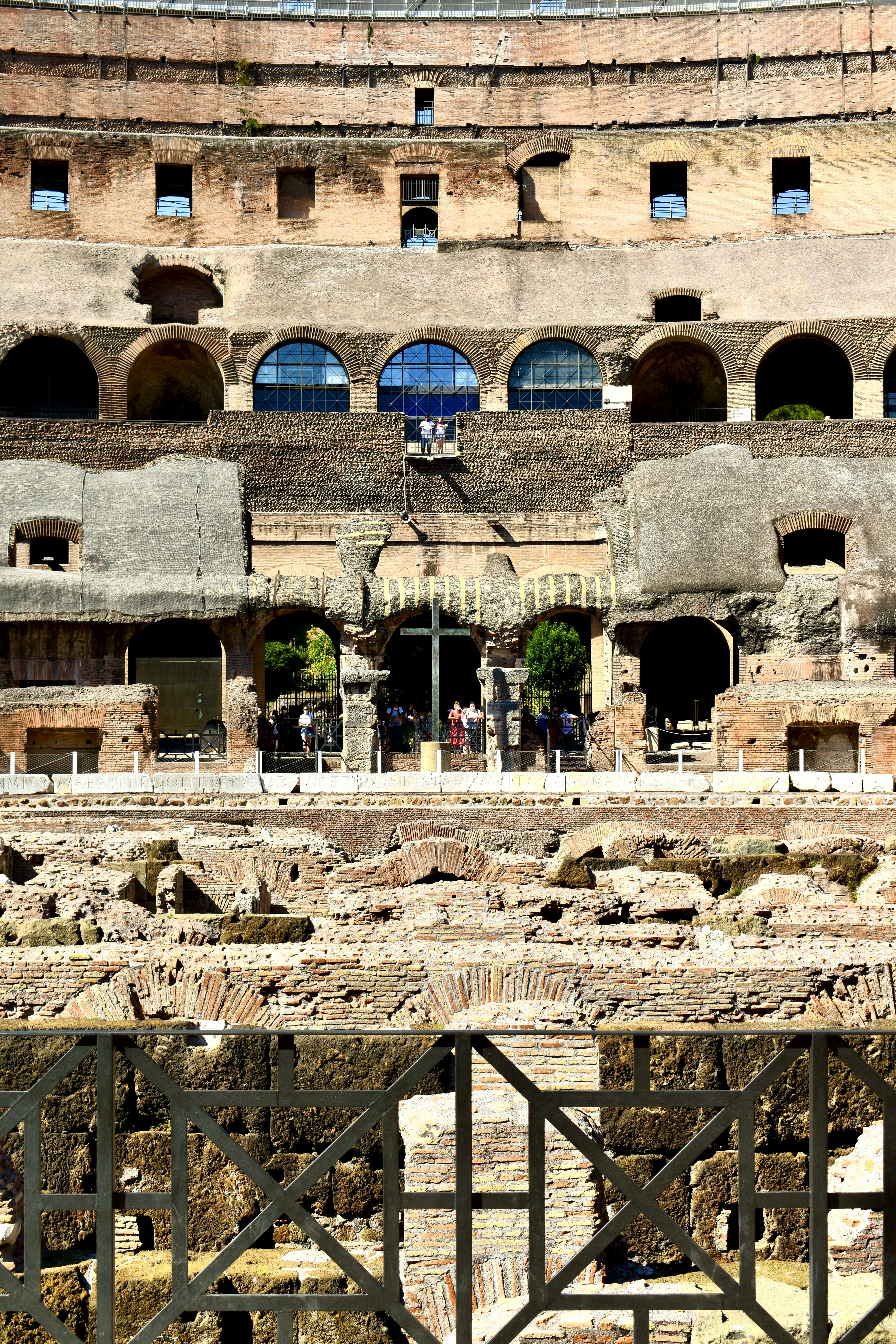 Interior view of the Colosseum showcasing its ancient architecture and audience areas. The remnants of the arena floor reveal historical layers beneath.