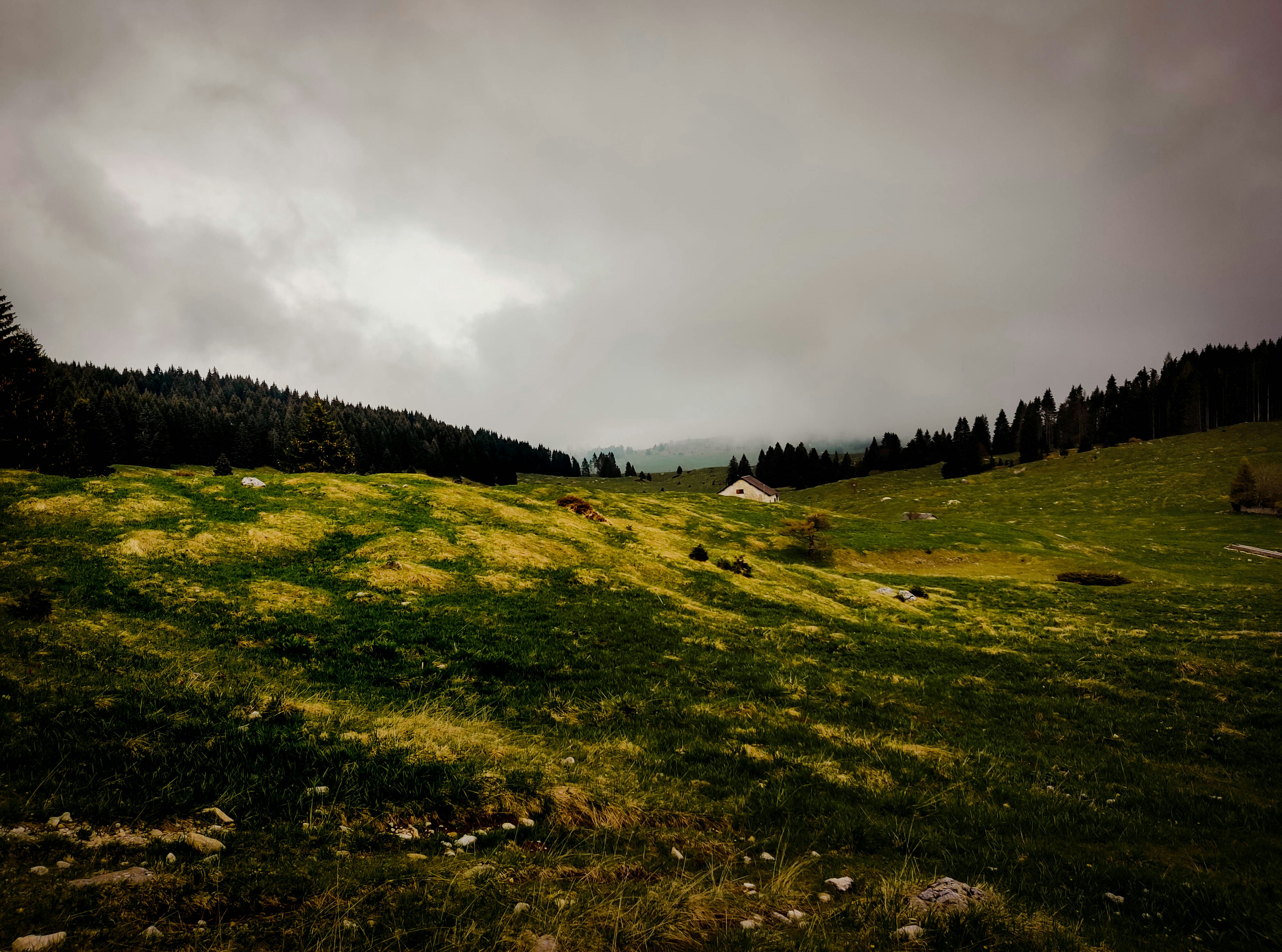 Lone Chalet on a Cresting Meadow Beneath Stormy Clouds