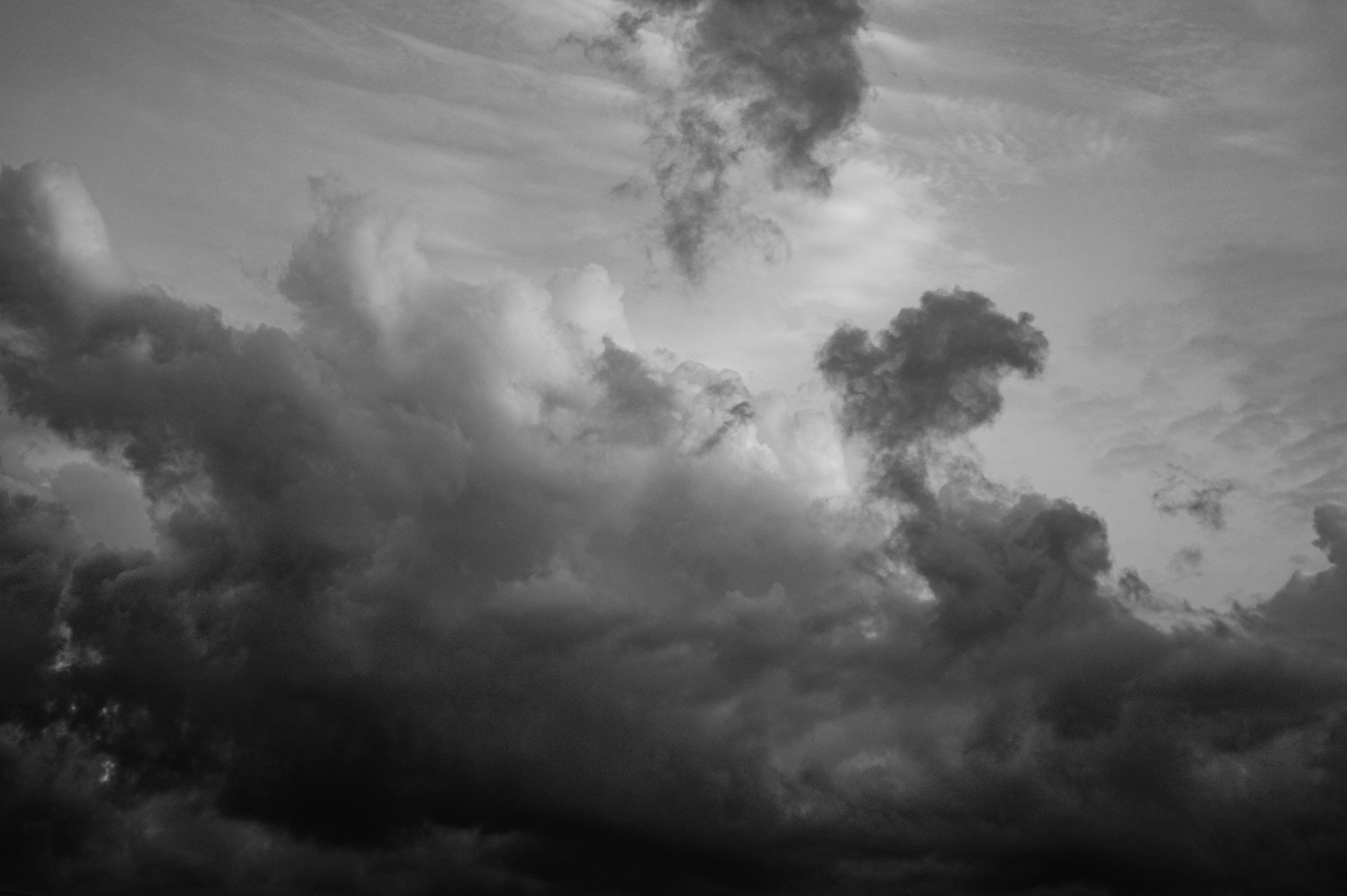Dramatic cloud formations swirl in a monochromatic sky, hinting at an impending storm. The interplay of light and shadow creates a dynamic atmosphere.