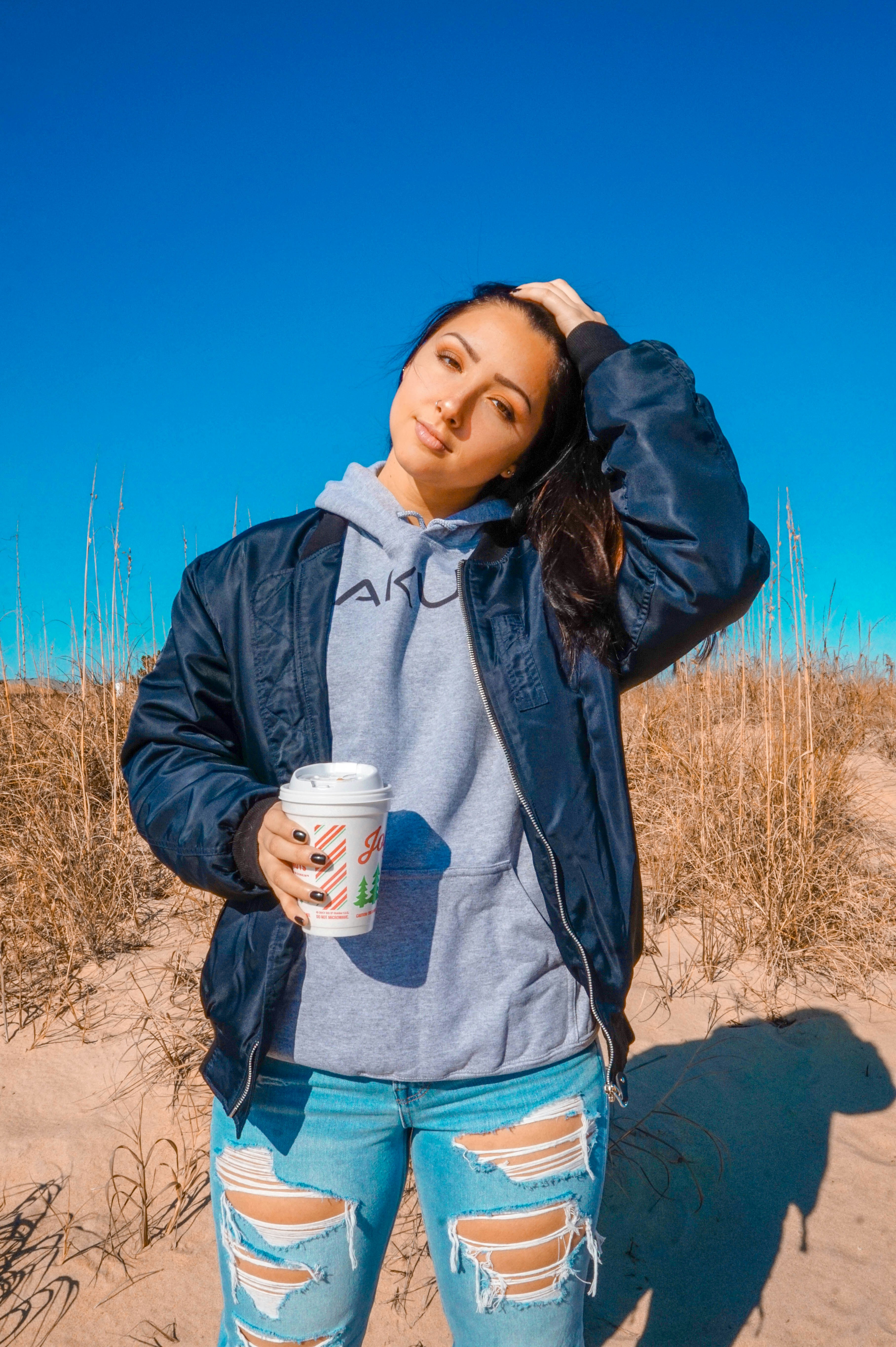 woman in black jacket holding white ceramic mug