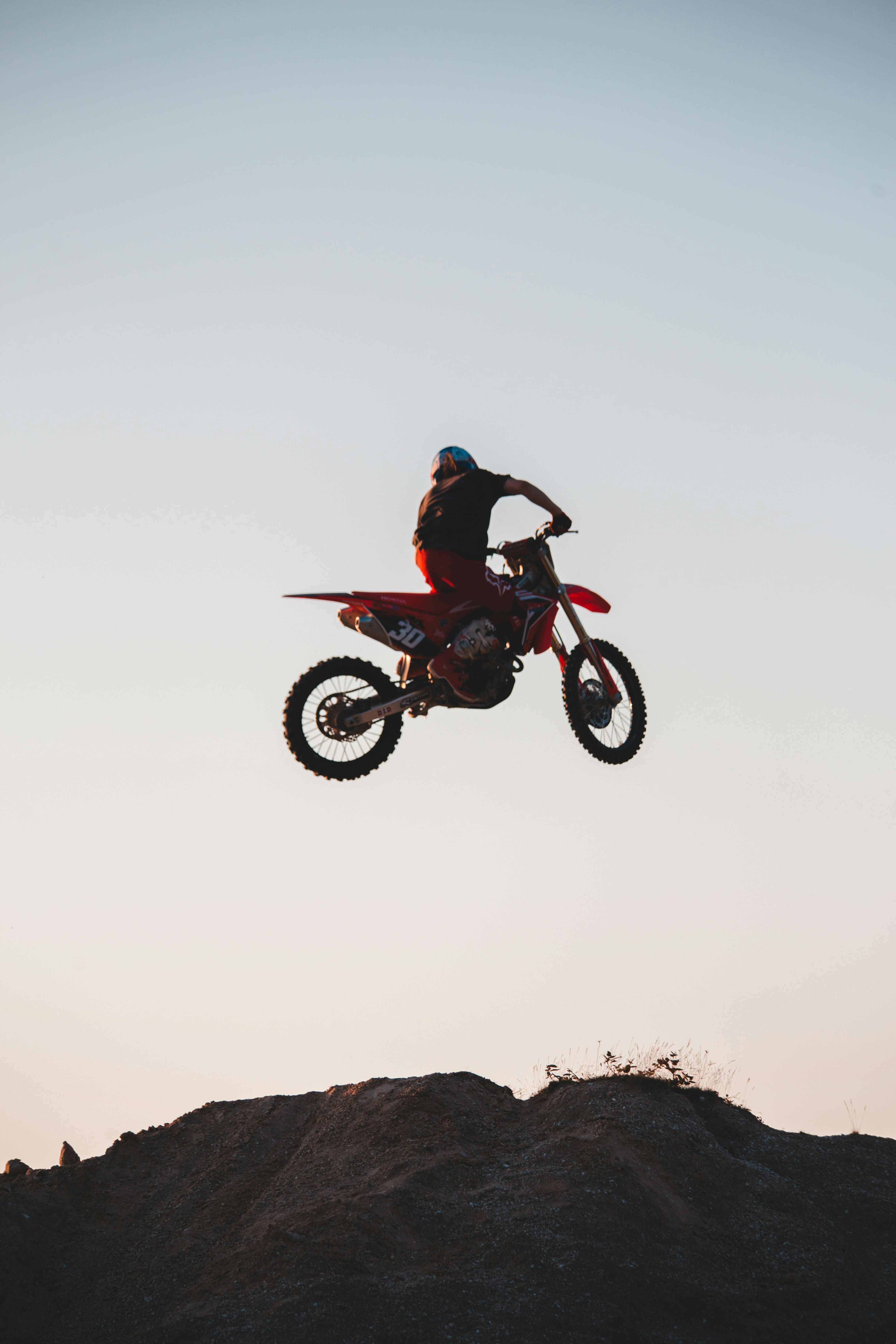Homme en veste noire à cheval sur un vélo de motocross noir et rouge ...