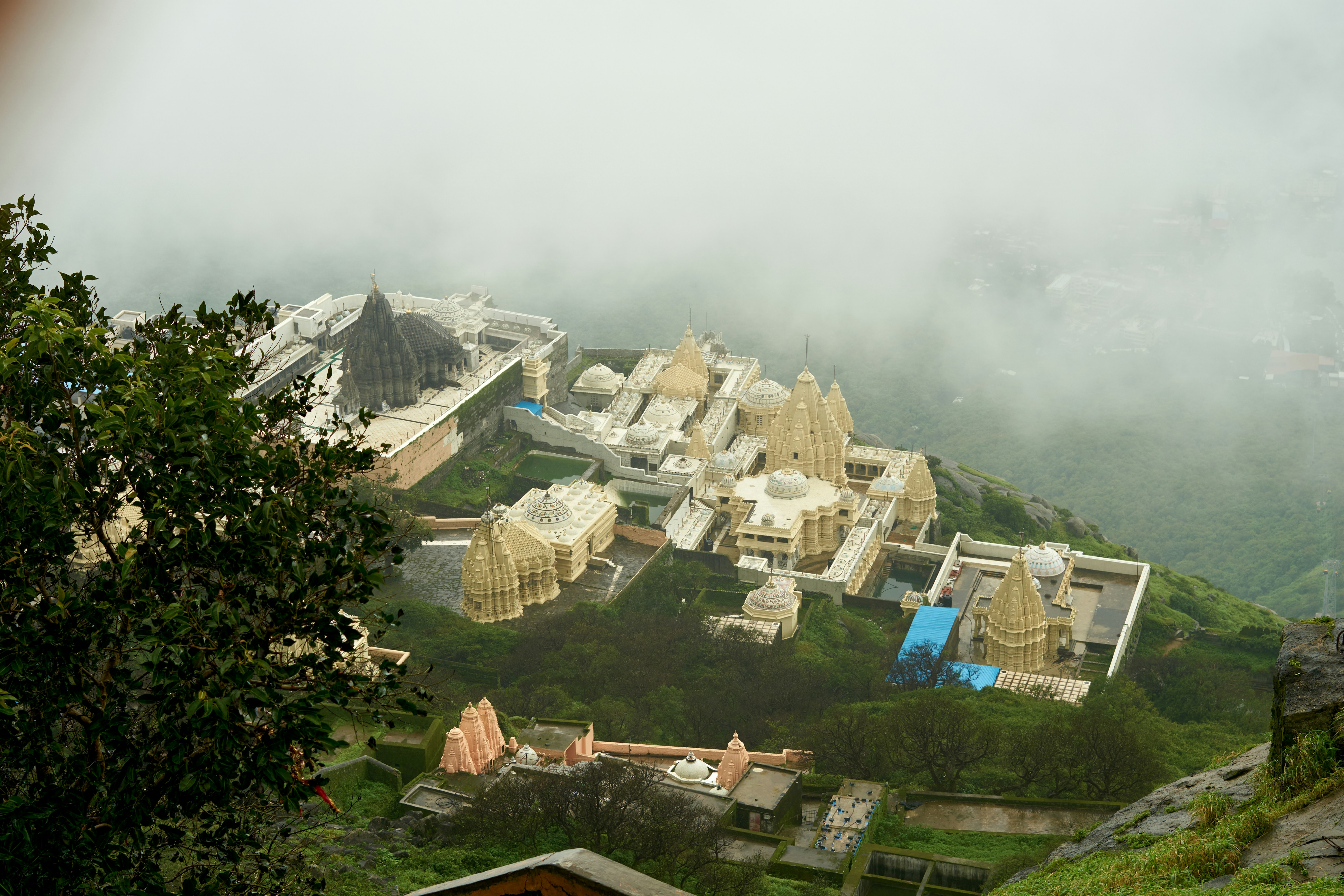 Ancient temples nestled in lush greenery, partially veiled by mist.