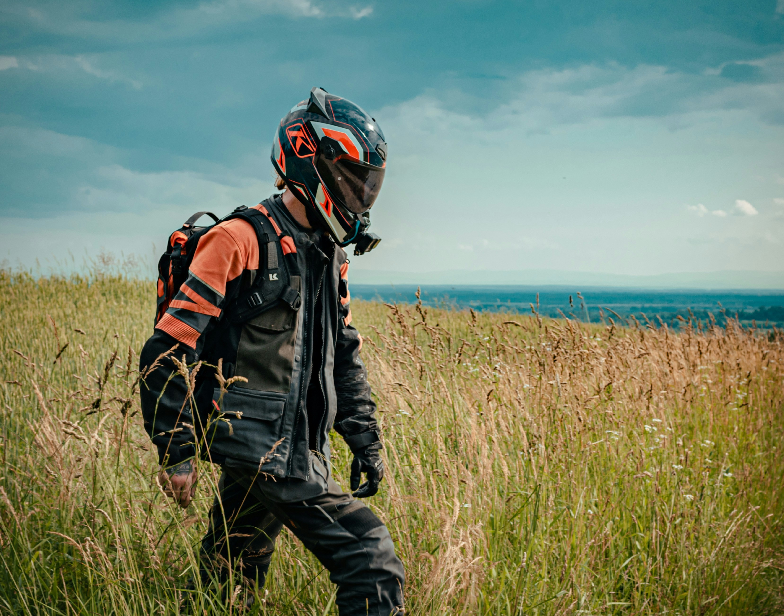 Motorcyclist navigating through tall grass under a dramatic sky, showcasing the spirit of adventure and exploration.