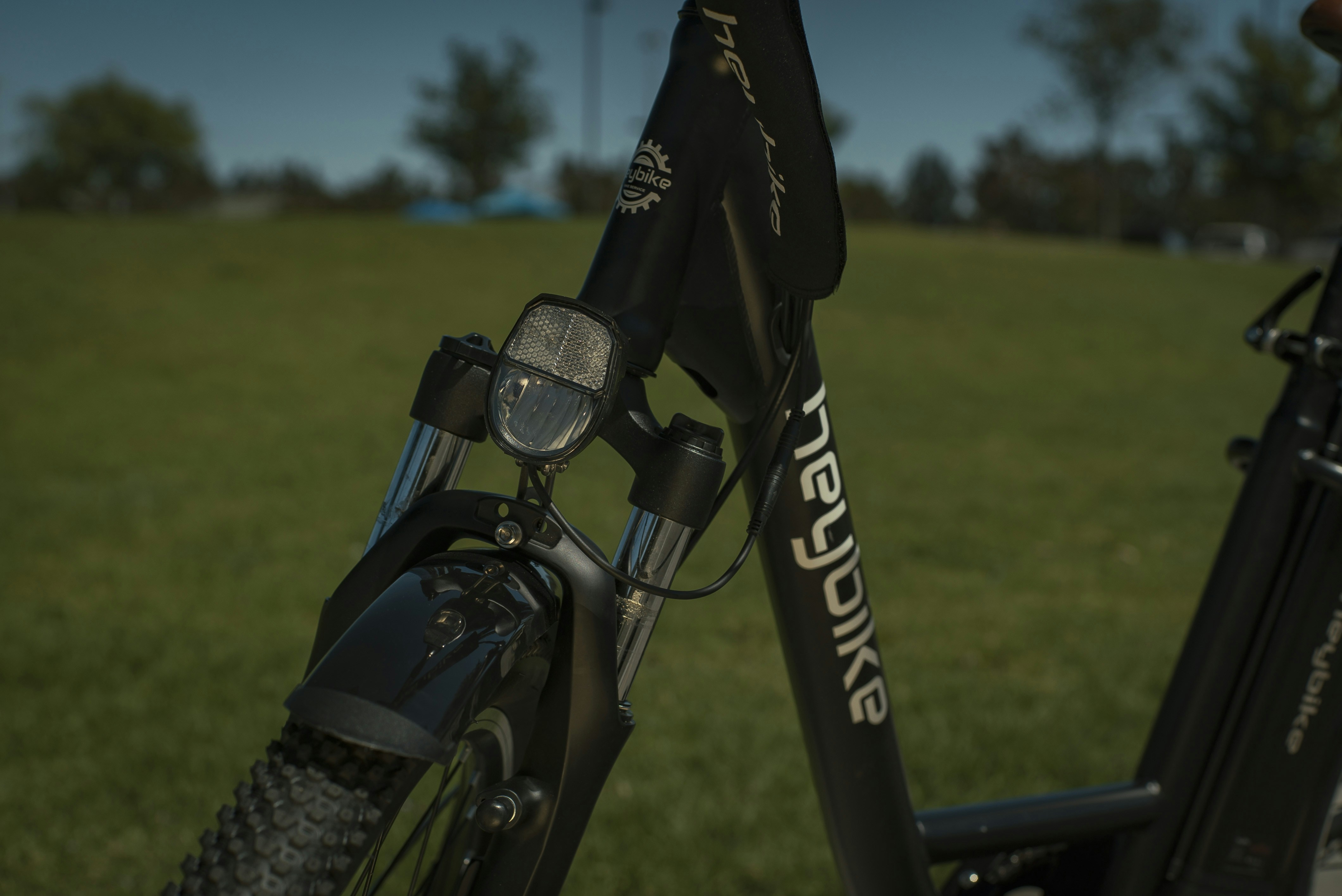 Close-up of Heybike Cityscape electric cruiser bike with LED light against a green park backdrop.