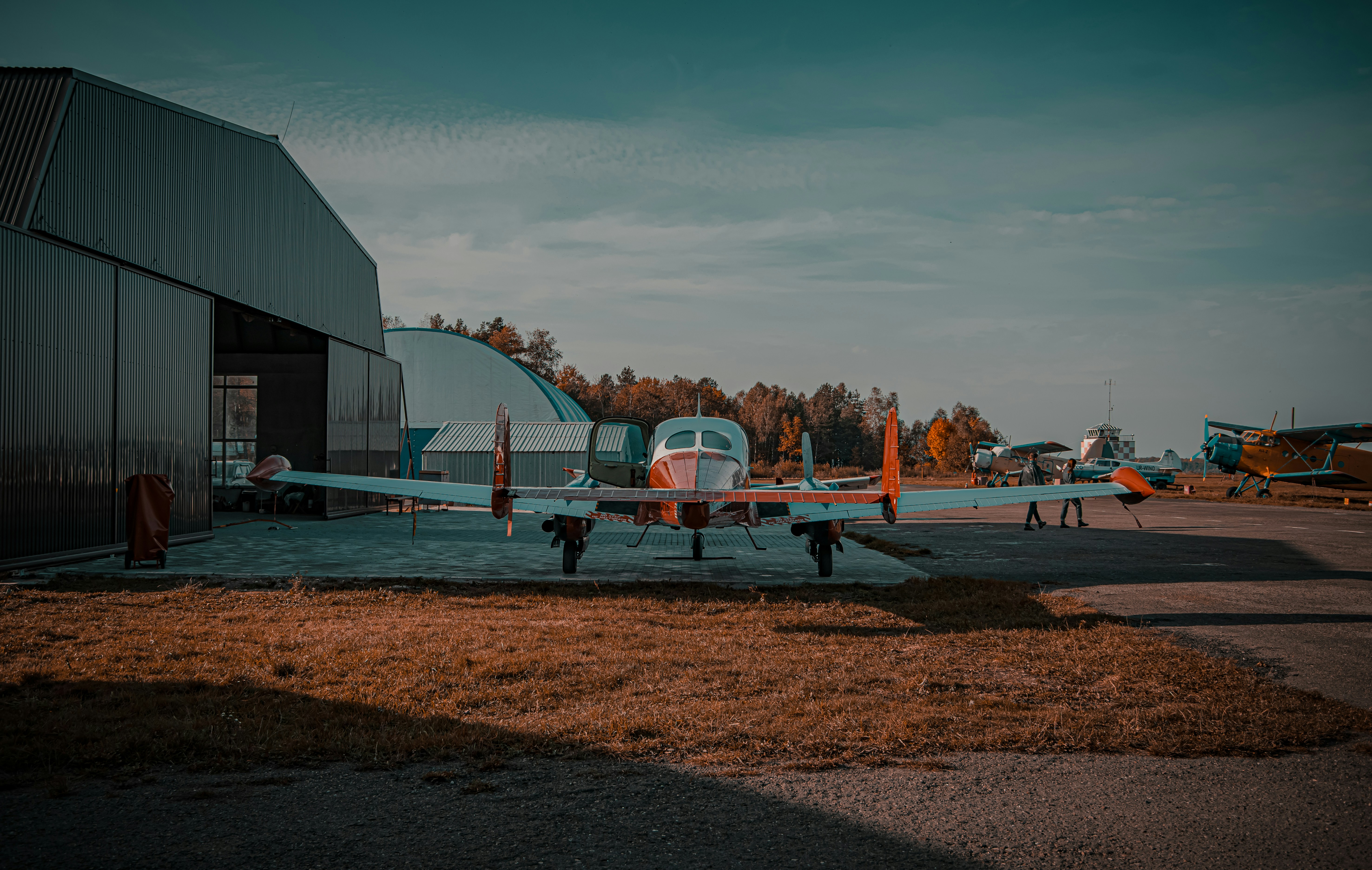 Vintage aircraft parked at an airfield, surrounded by hangars and other planes. The scene captures the essence of aviation tranquility.