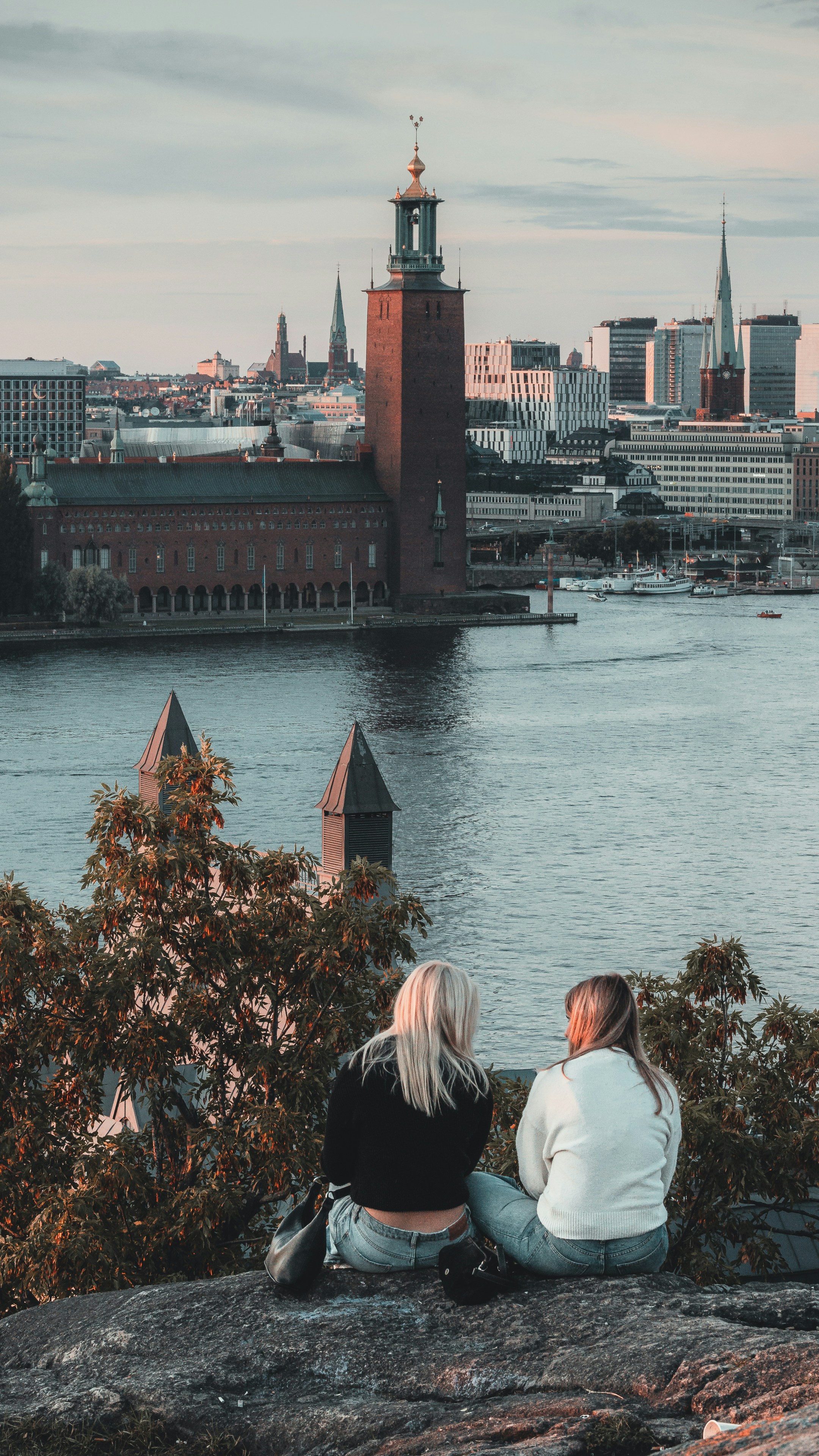 Two Friends Overlook the City by the Waterfront at Dusk