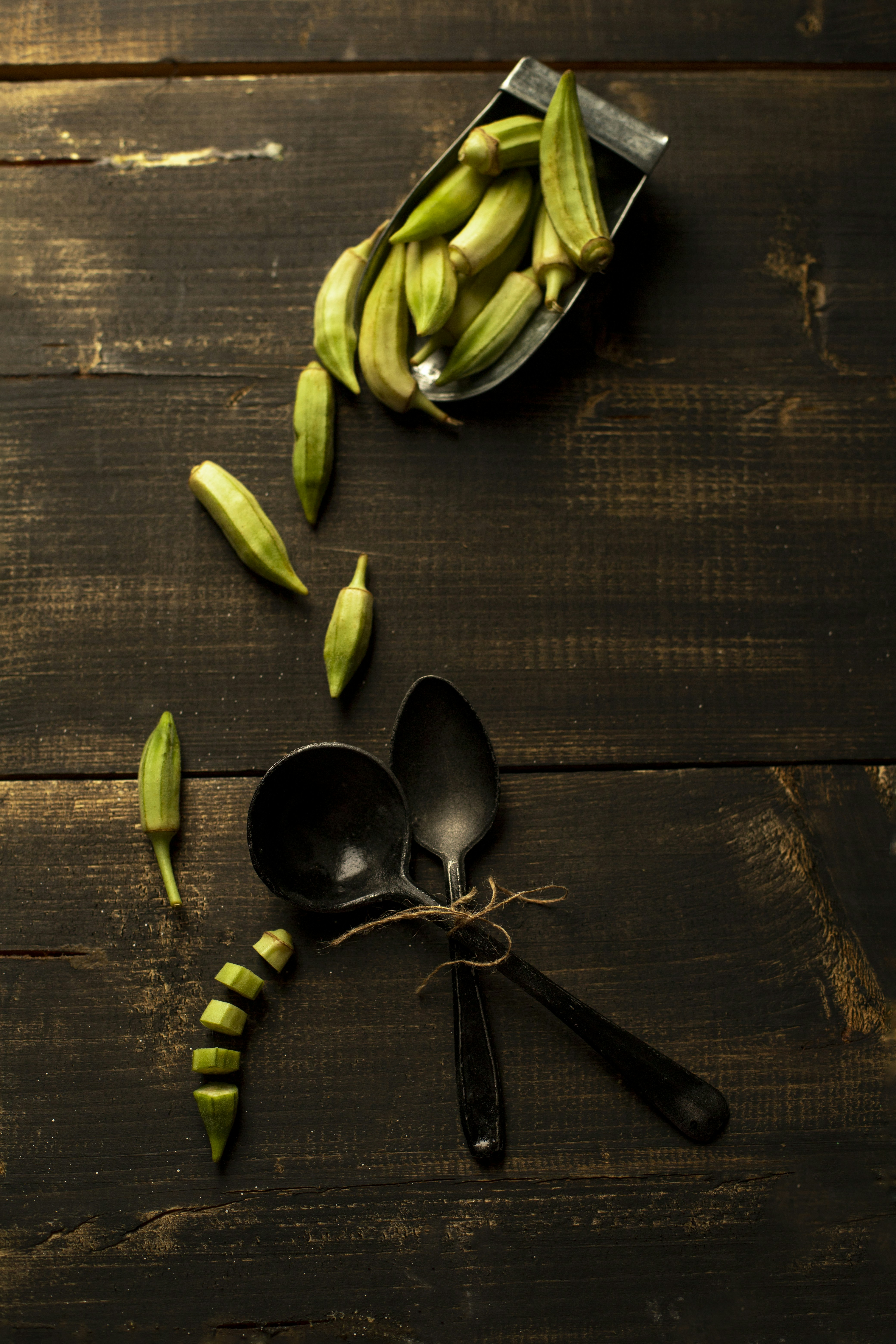 Opposites Attract: Green Pods and Black Spoons on a Weathered Board
