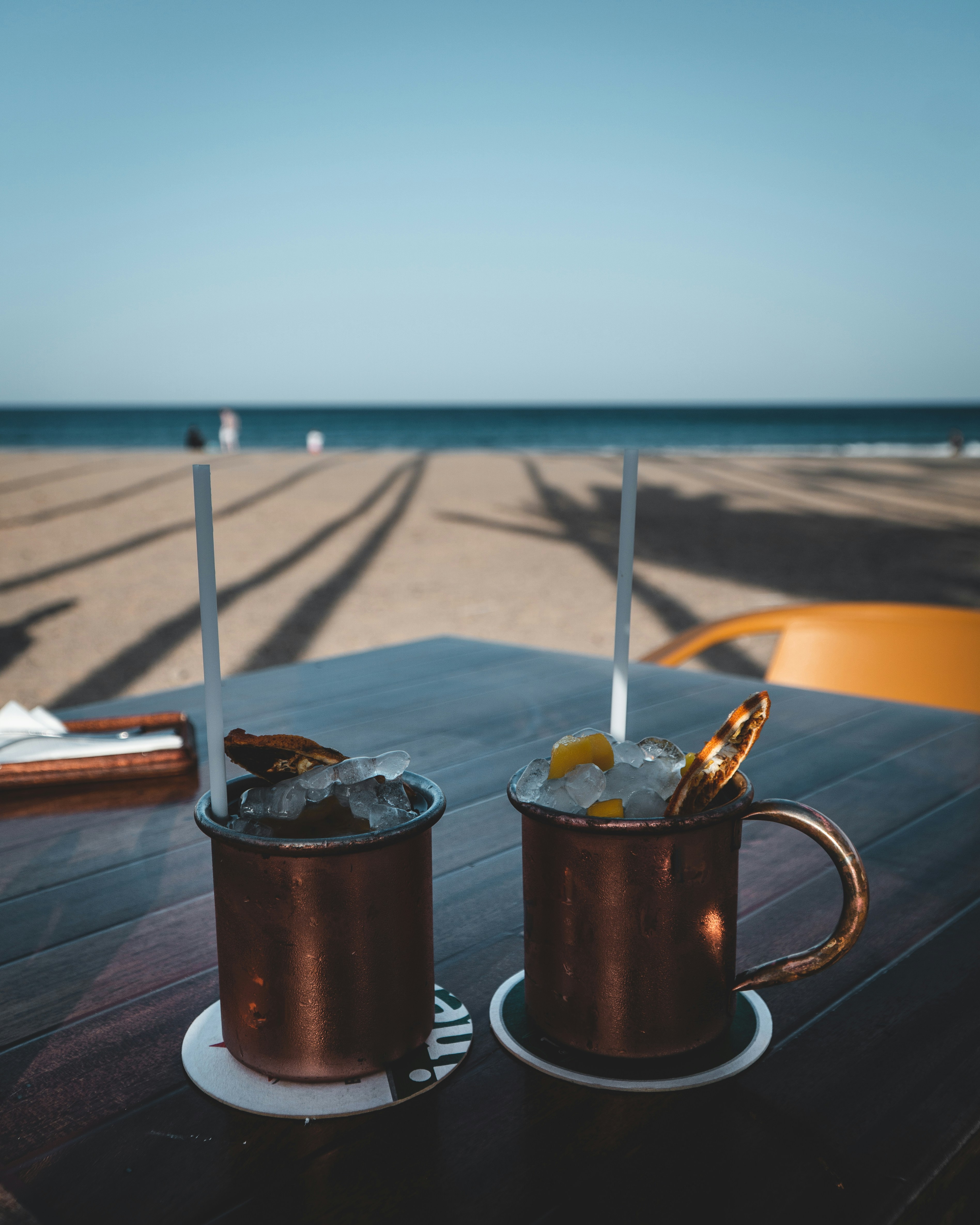 Copper Mugs on a Beachfront Table: Ice, Citrus, and Sunlit Shadows