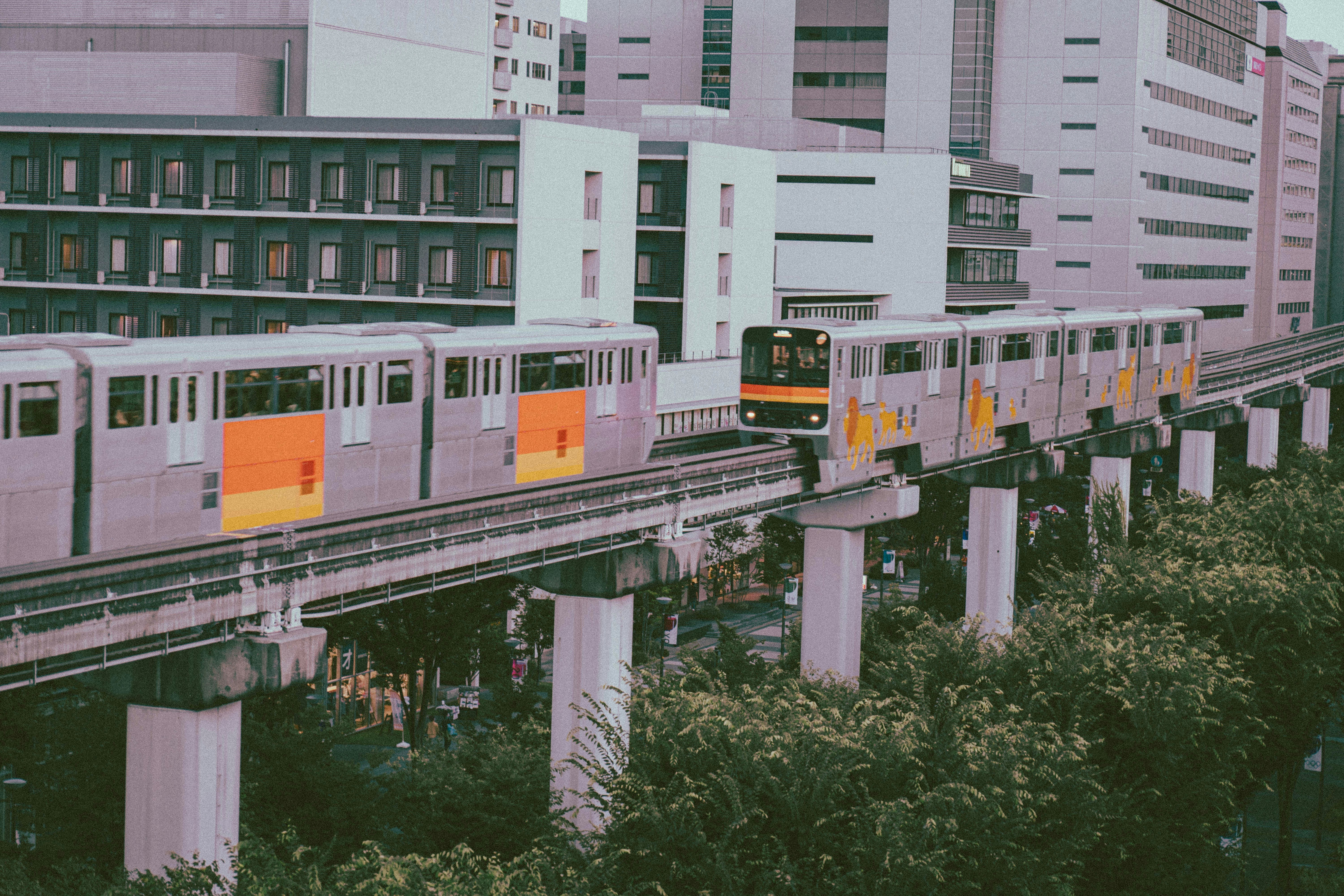 Monorail trains glide above a bustling cityscape, framed by modern architecture and lush greenery.