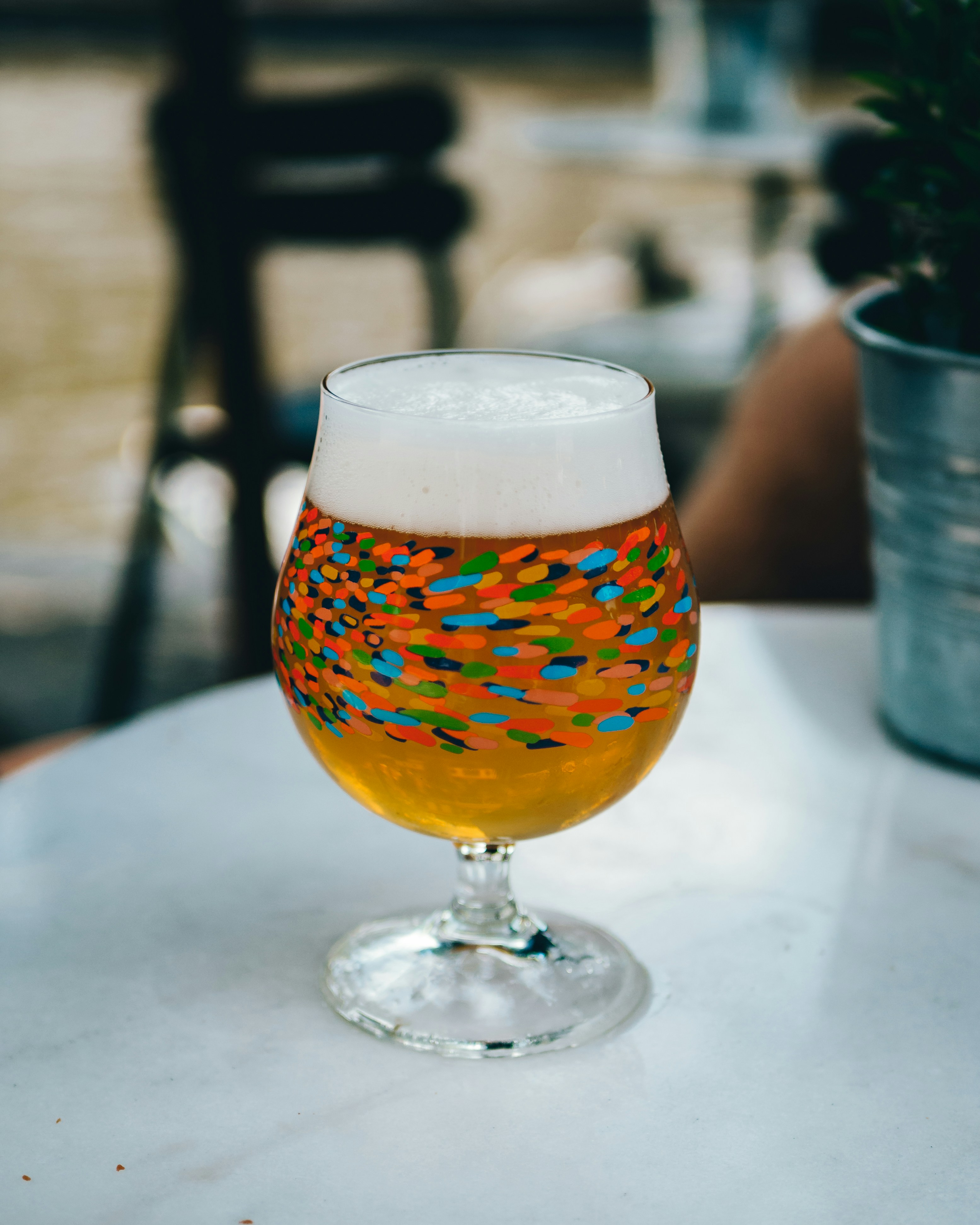 Patio Prism: A beer glass swirling with confetti colors on a sunlit table