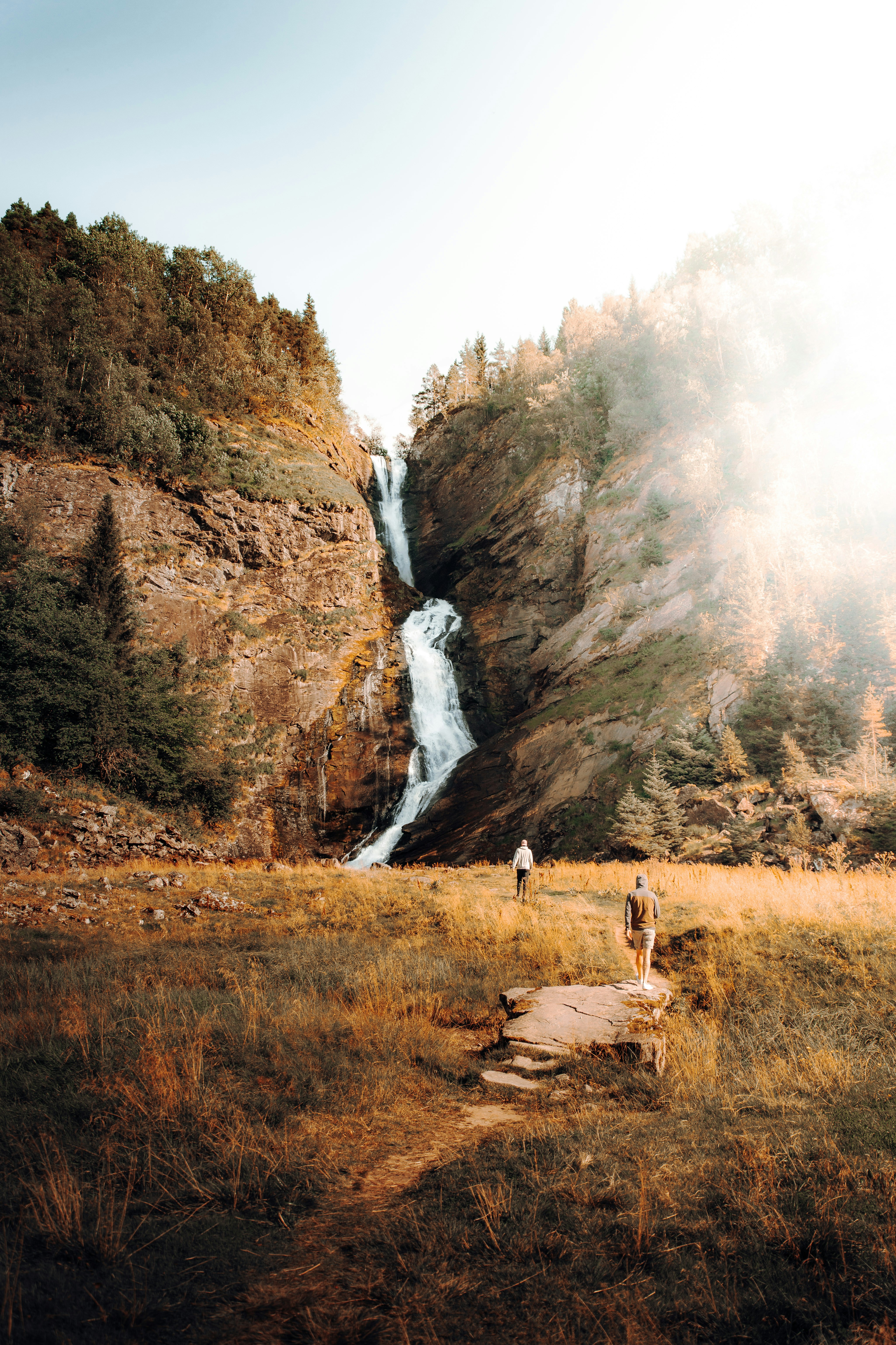 Hikers at the Base of a Cascading Canyon Waterfall