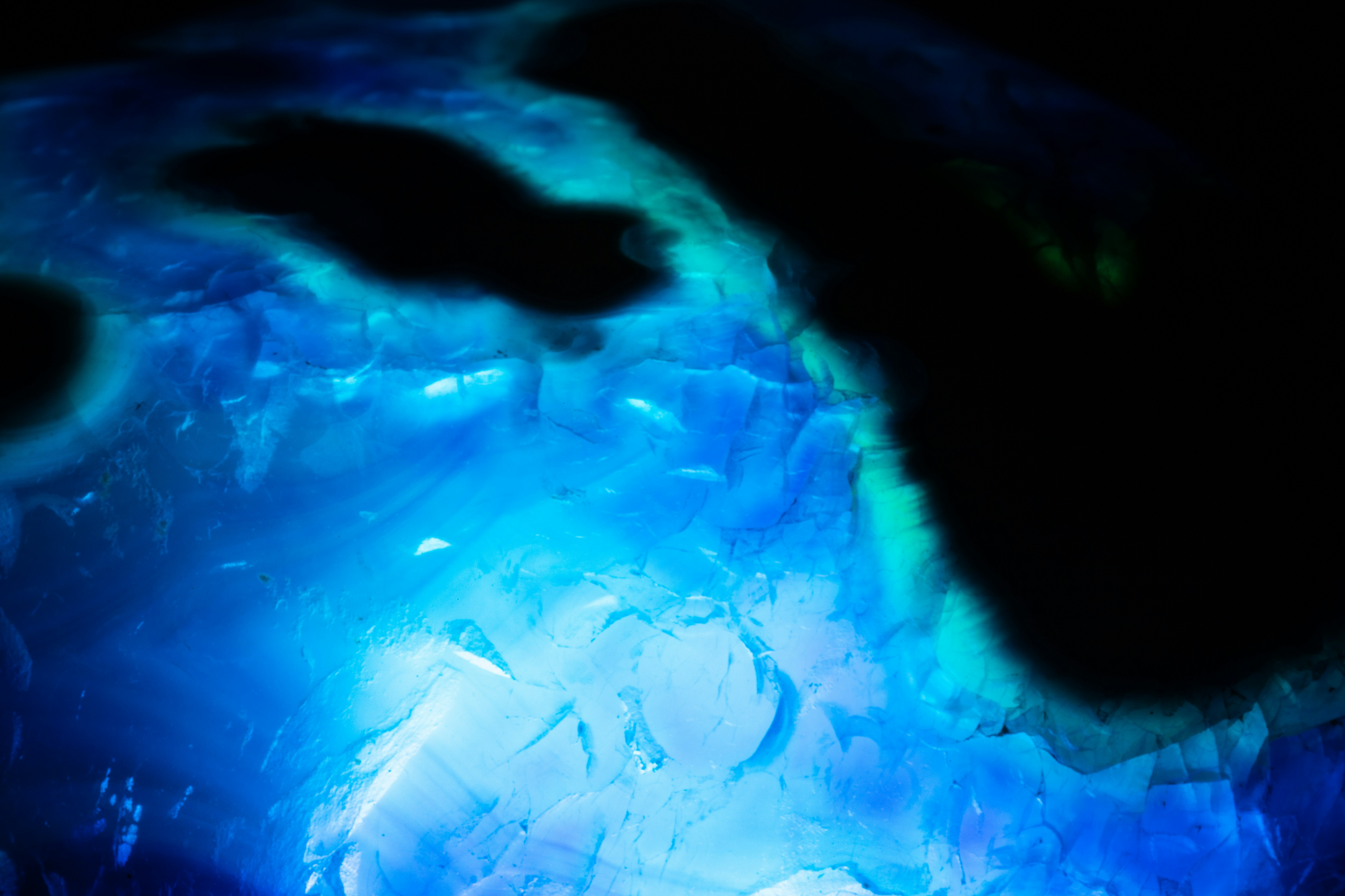 Vibrant blue and green hues blend together, creating an abstract representation of ocean depths illuminated by light.