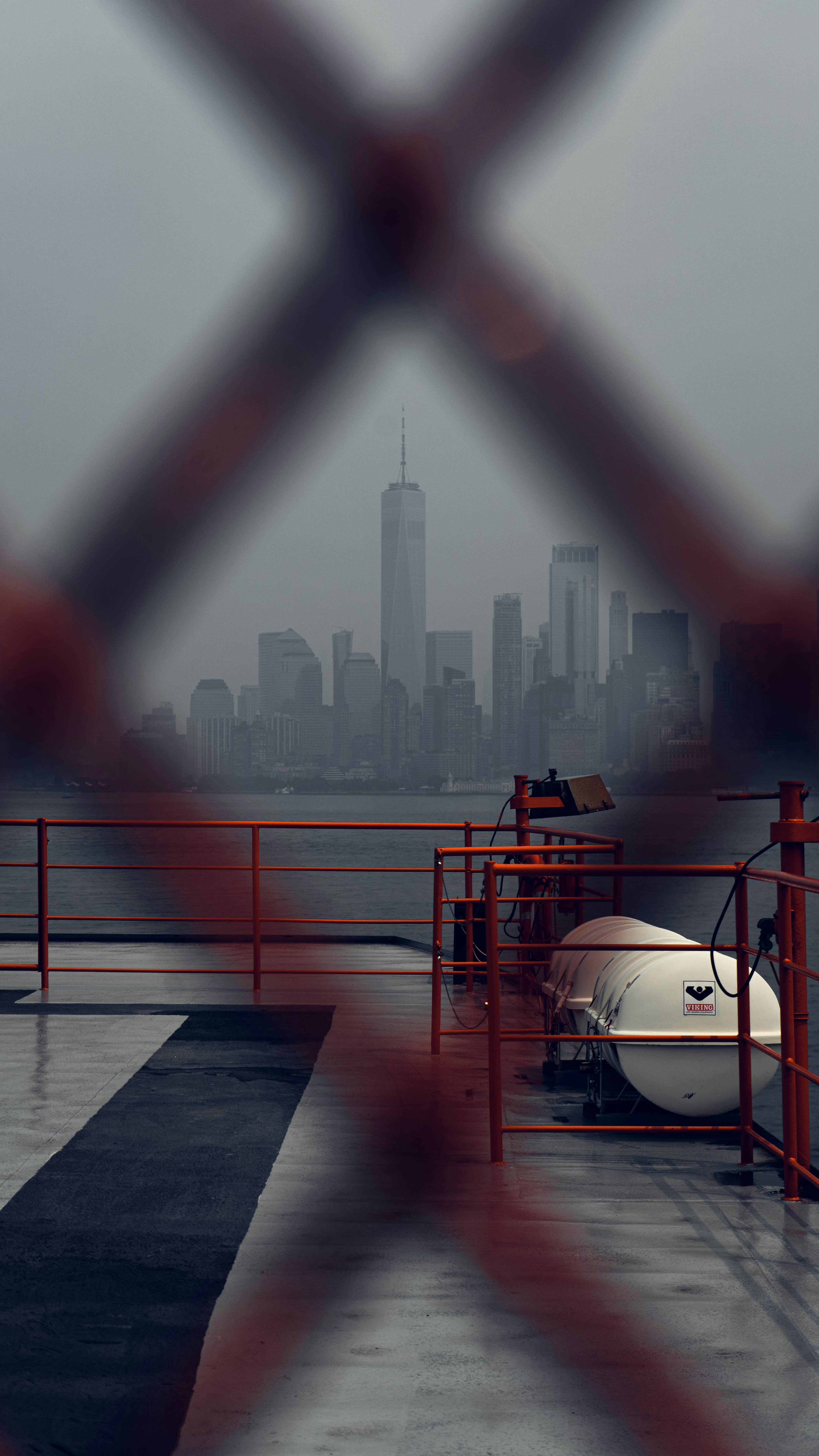 Manhattan Through a Red Lattice: A Harbor View Framed by Rust