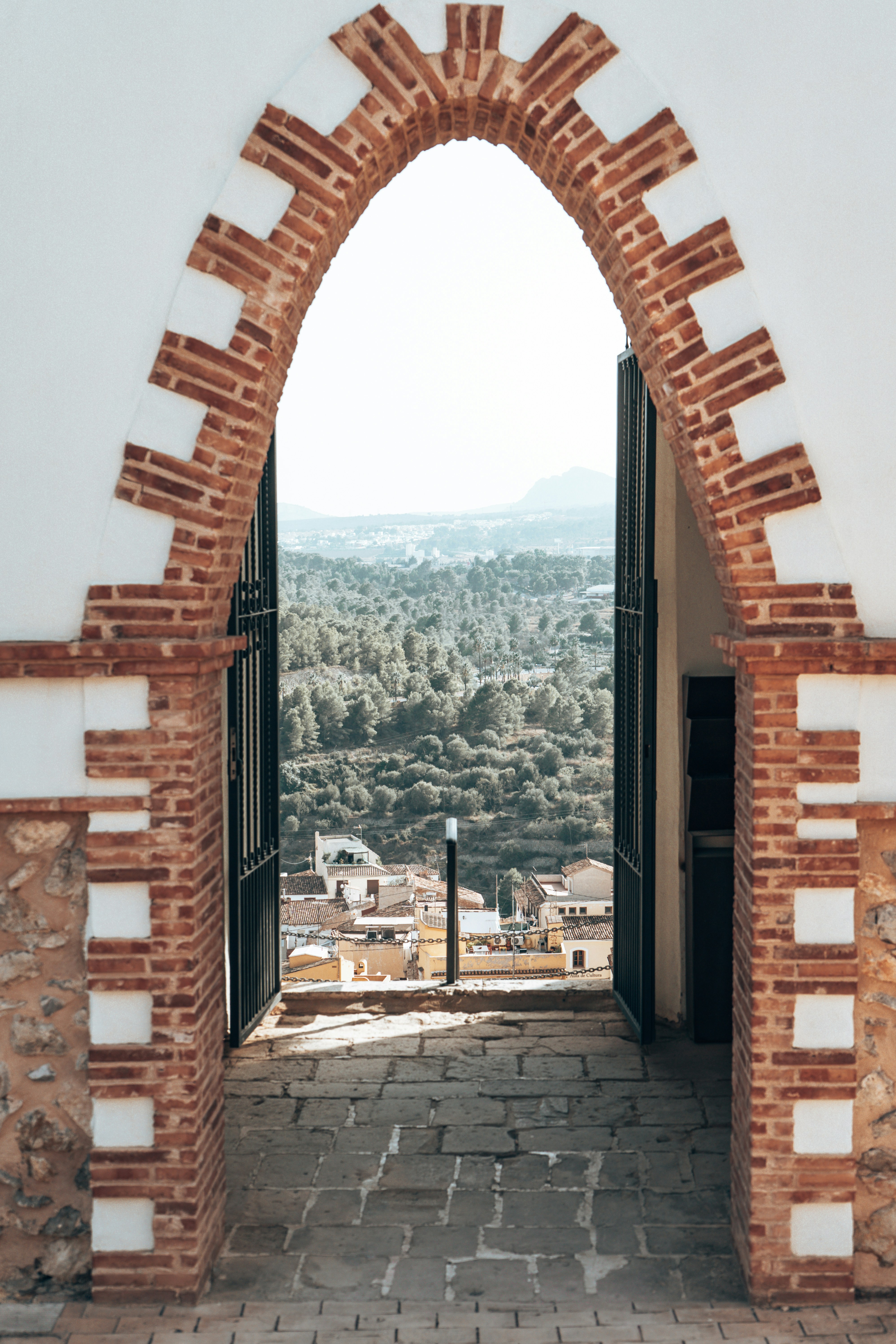 Through the Brick Arch: A Quiet Valleyscape Opens Beyond Iron Gates