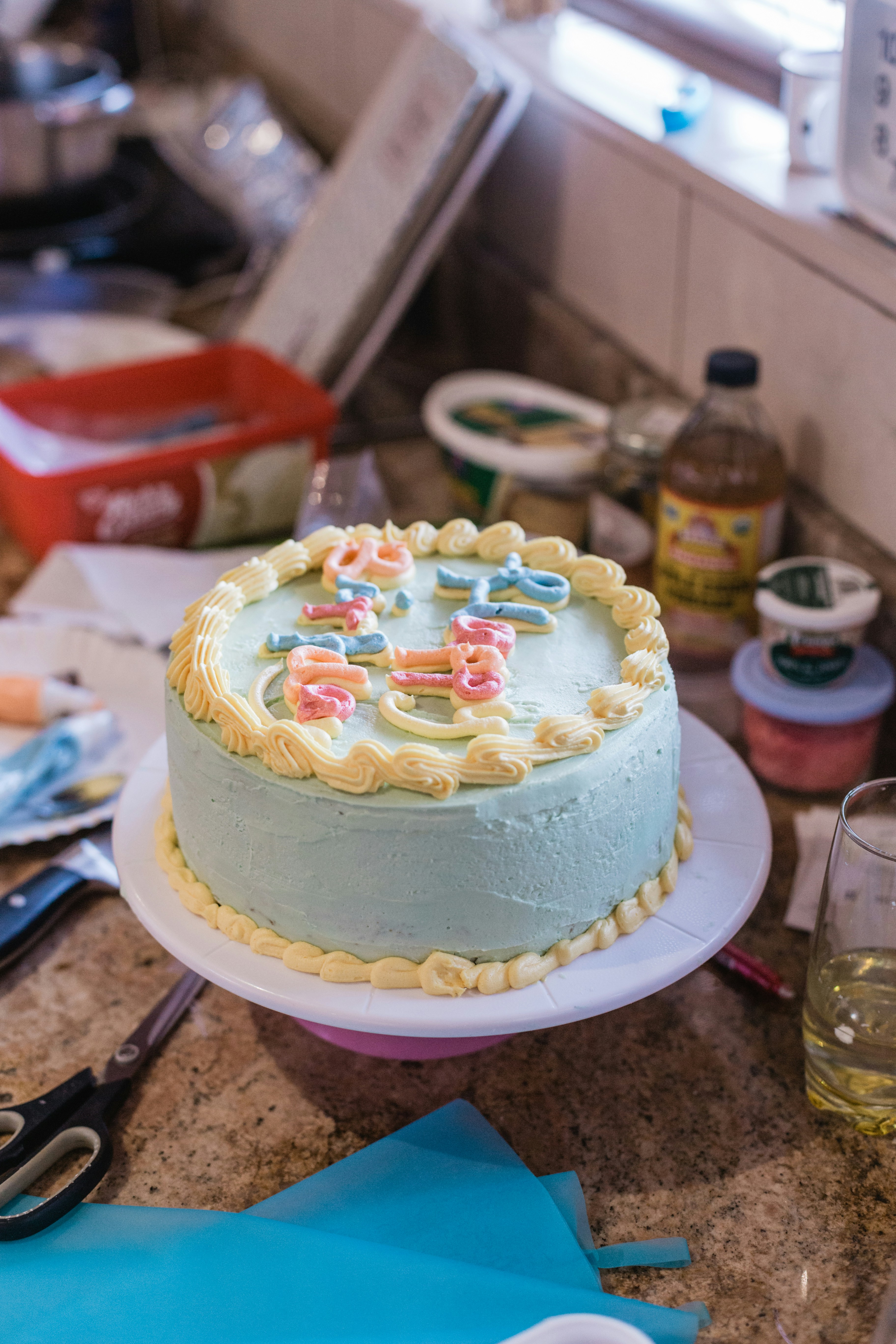 Blue Buttercream Birthday Cake on a Cluttered Kitchen Counter