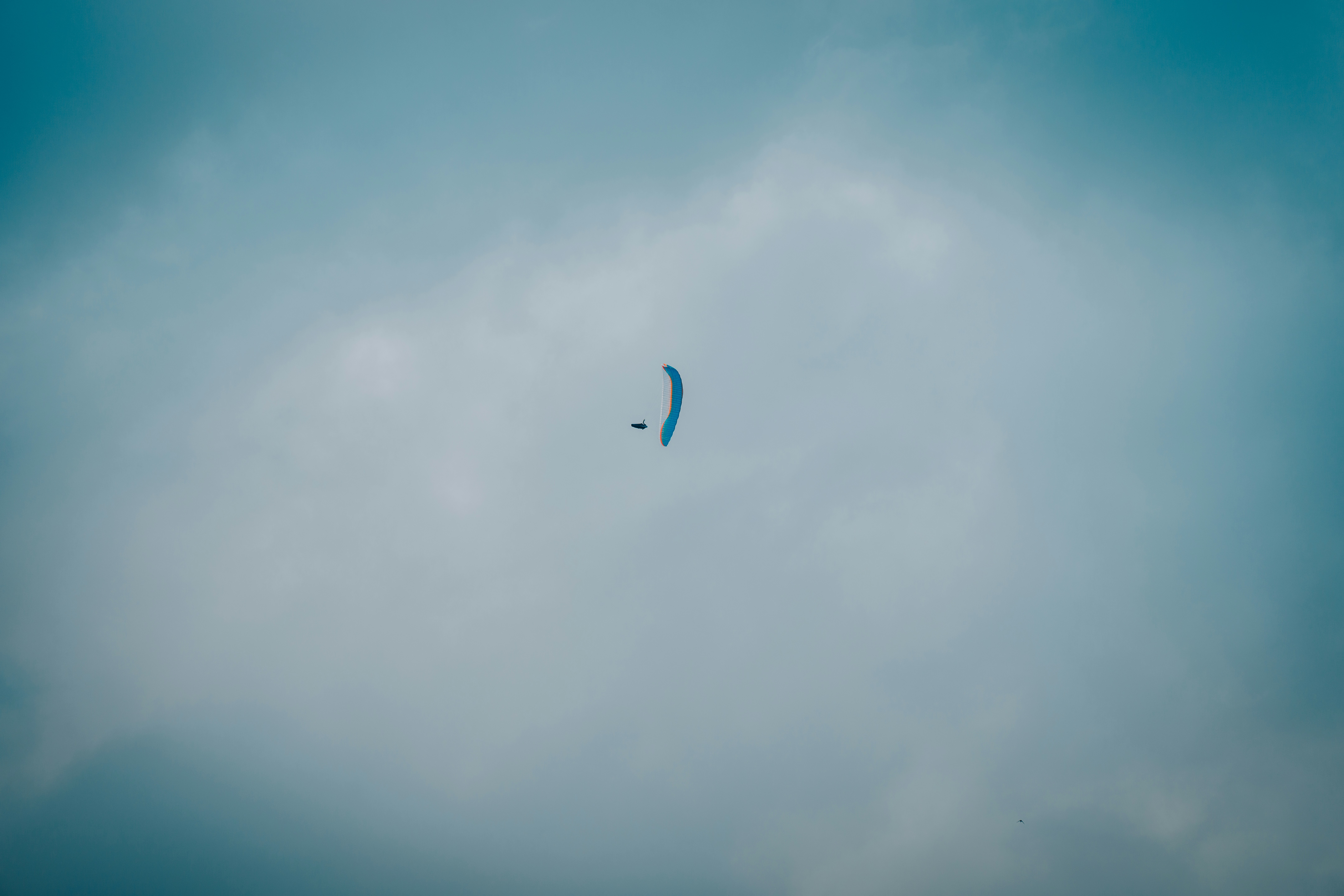 Blue Arc Over Quiet Skies: A Solo Paraglider in a Misty Panorama