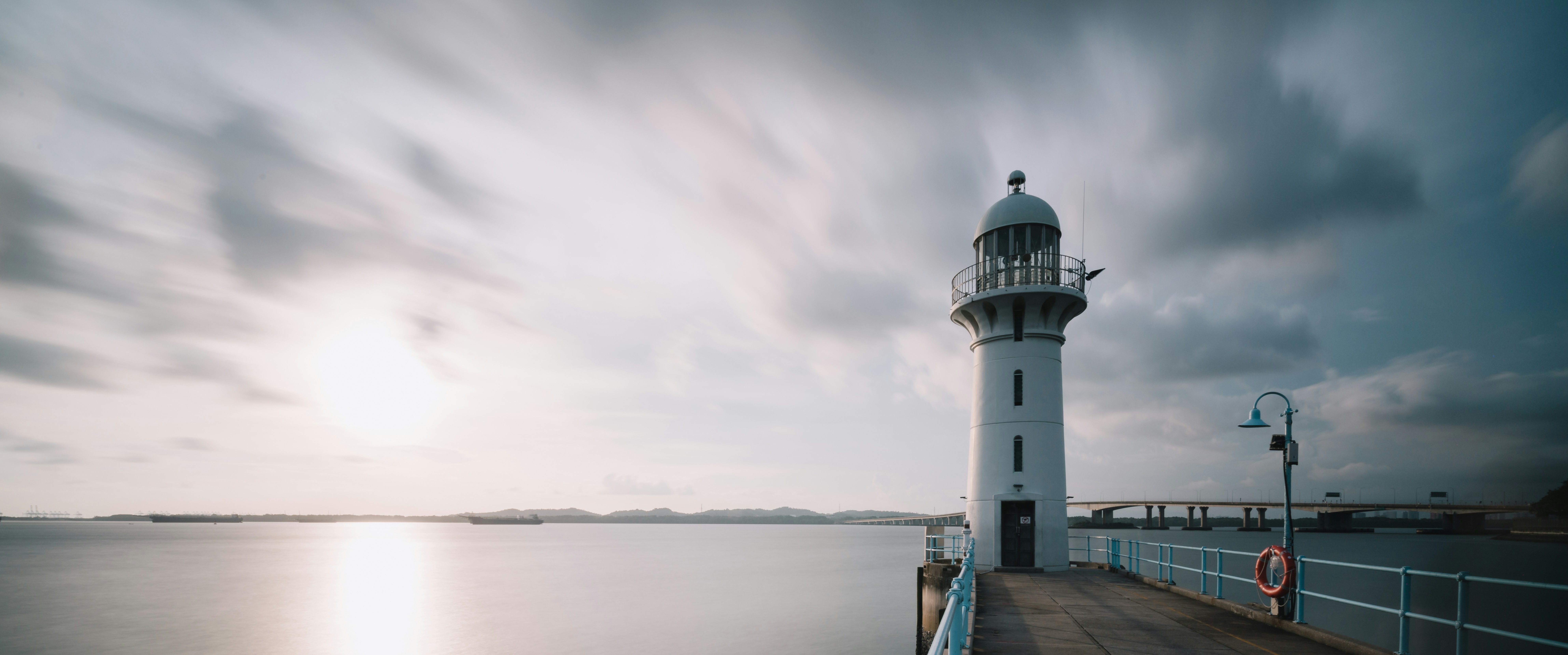 White and black lighthouse near body of water under cloudy sky during ...