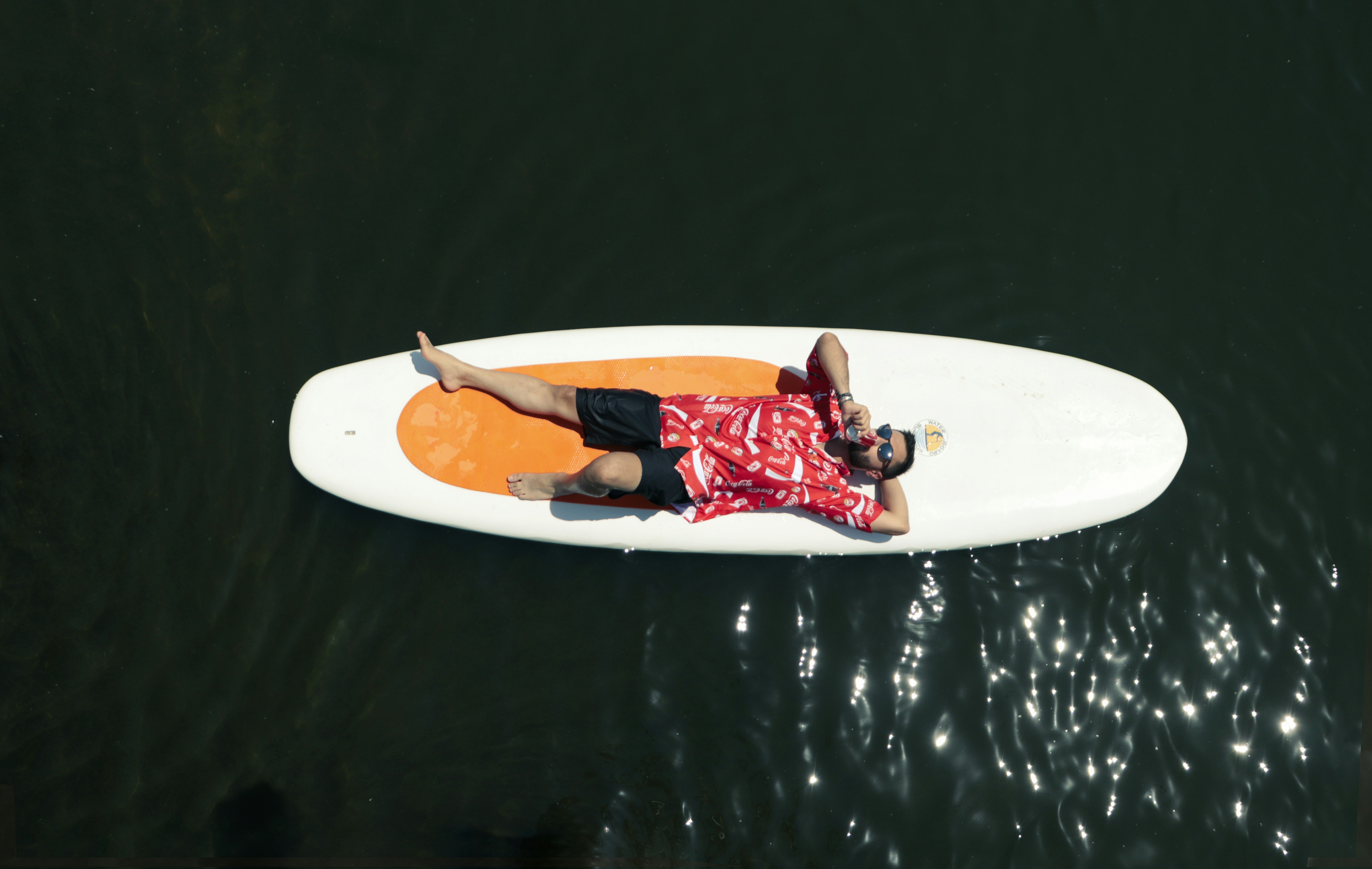 A person relaxing on a paddleboard, draped in a vibrant red towel, floating peacefully on a calm body of water.