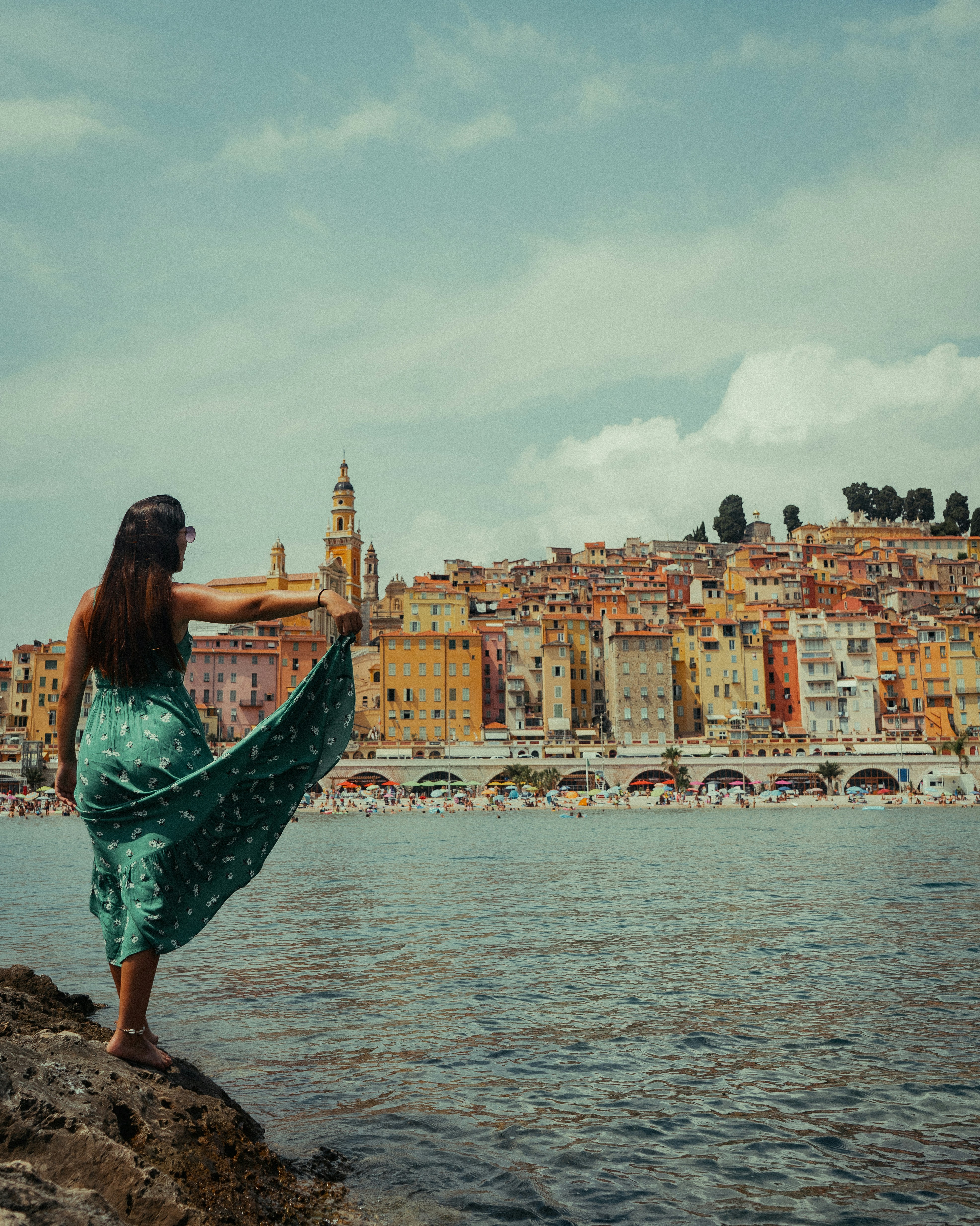 Azure scarf, sunlit shore: a lone figure framing a seaside village