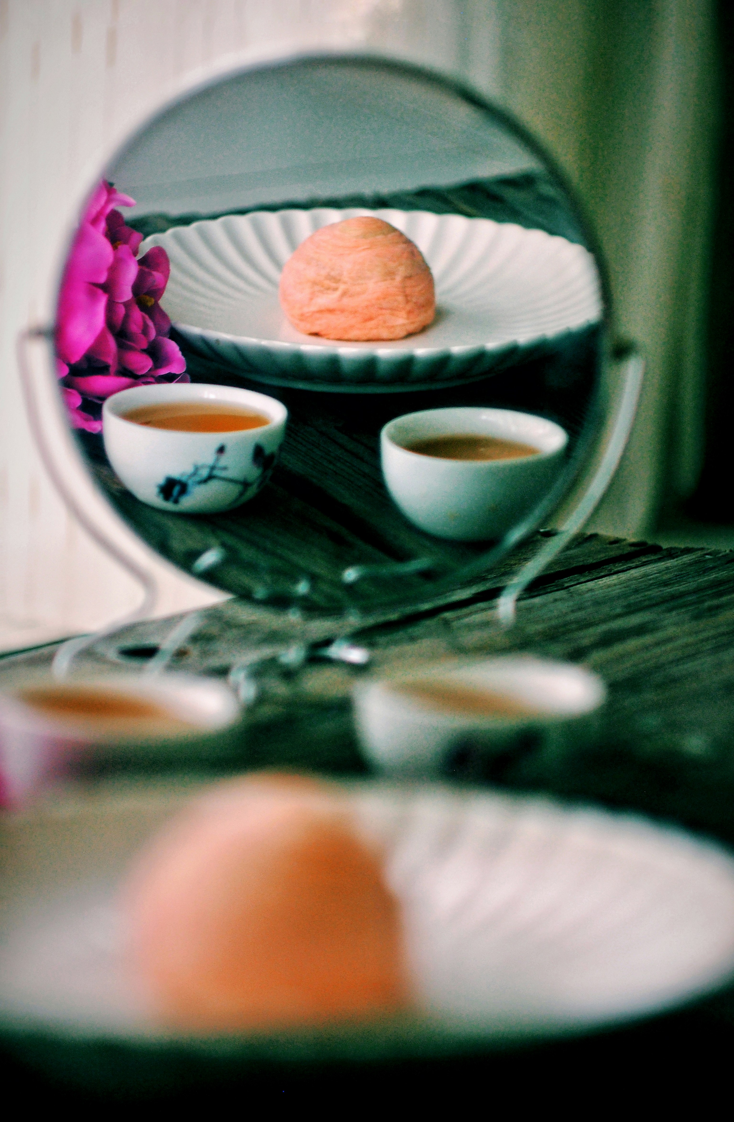Round Mirror Reverie: An Orange Bun Amid Tea Cups